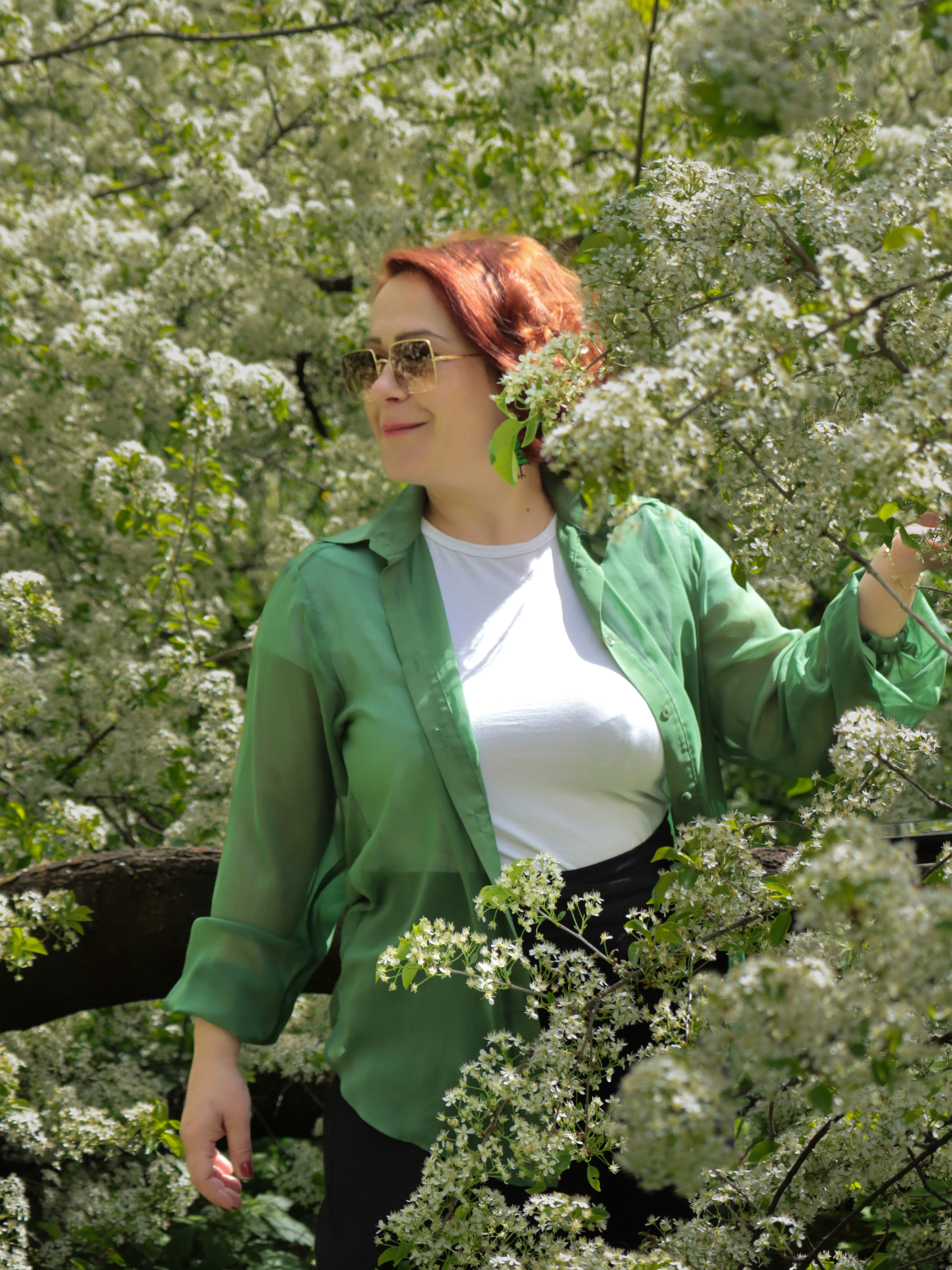 Charmed in Bloom: A Green Jacket Amid White Blossoms