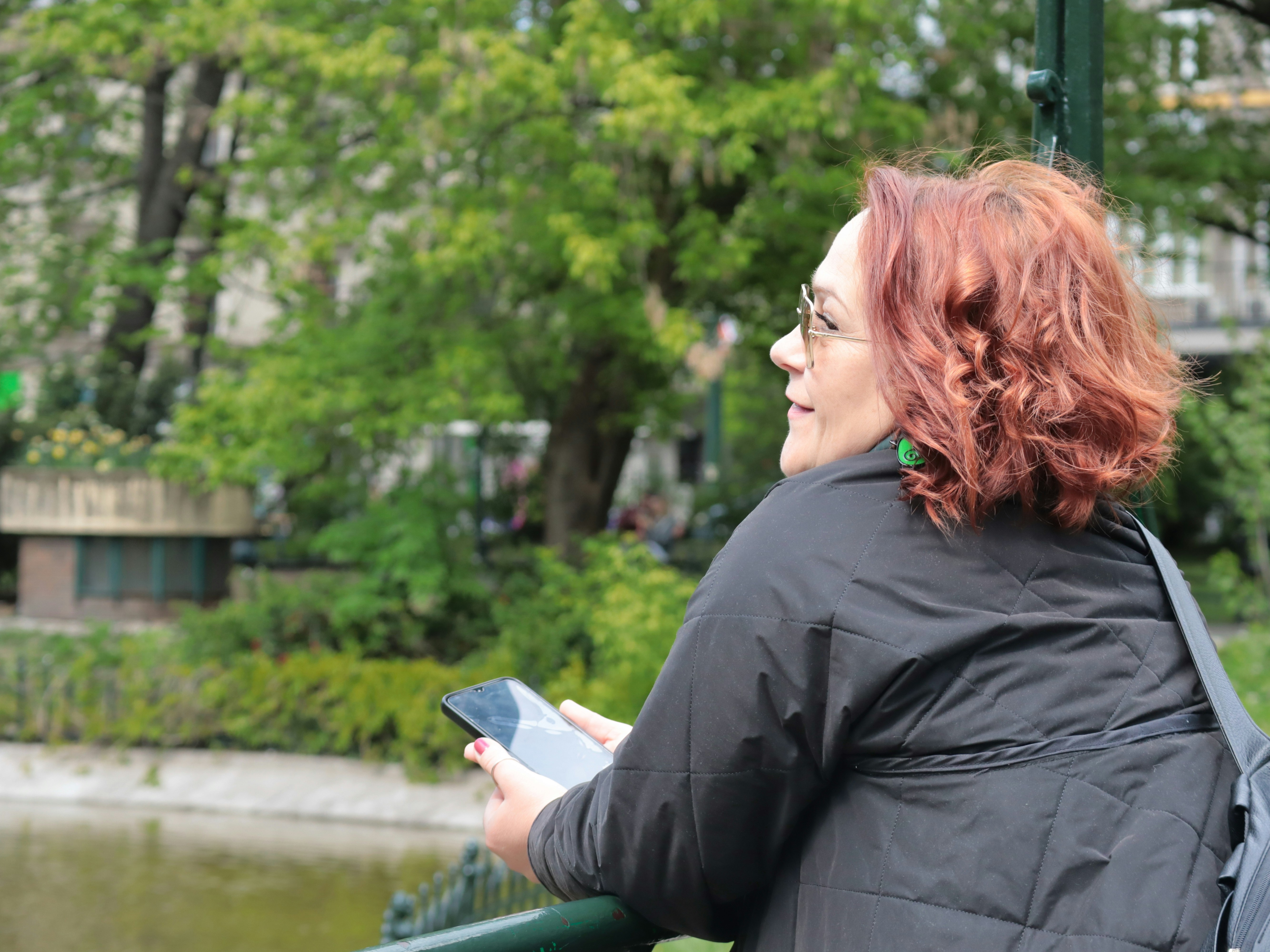 Portrait of a Red-Haired Woman in a Green Park Reading a Phone