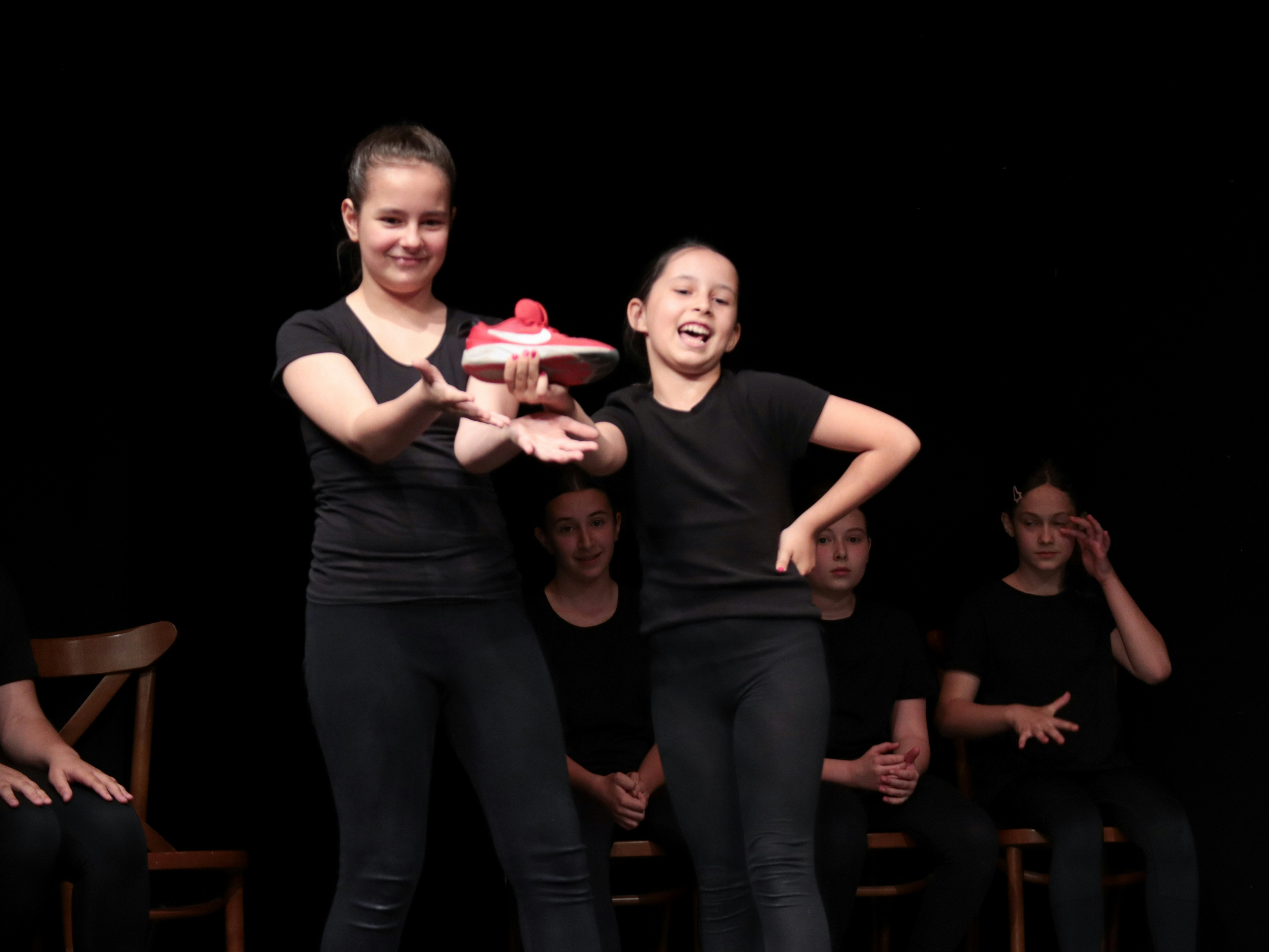 Pink-Top Toy Moment: Dancers Share a Playful Pose on Stage