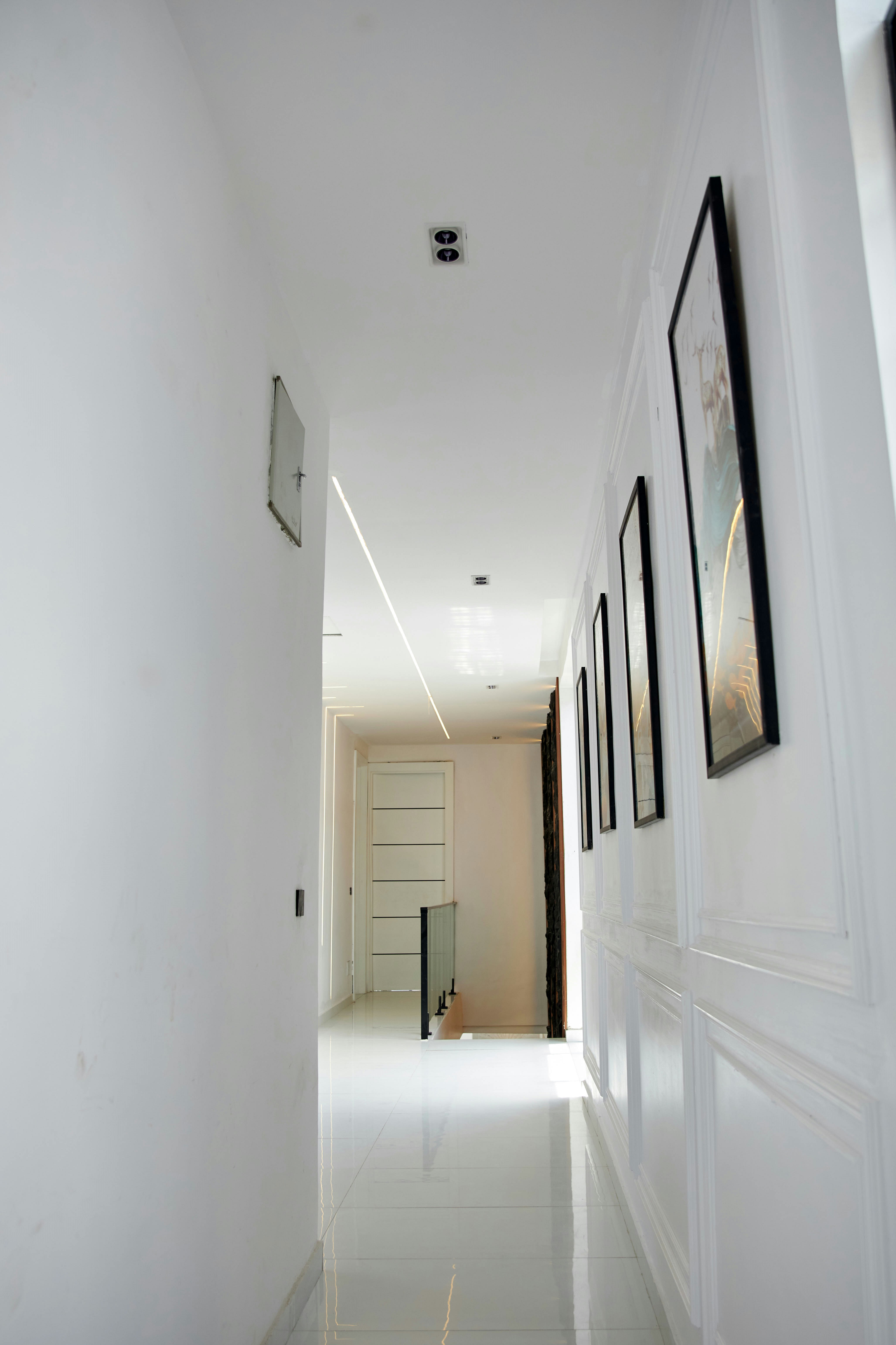 Bright White Corridor with Framed Art Reflections