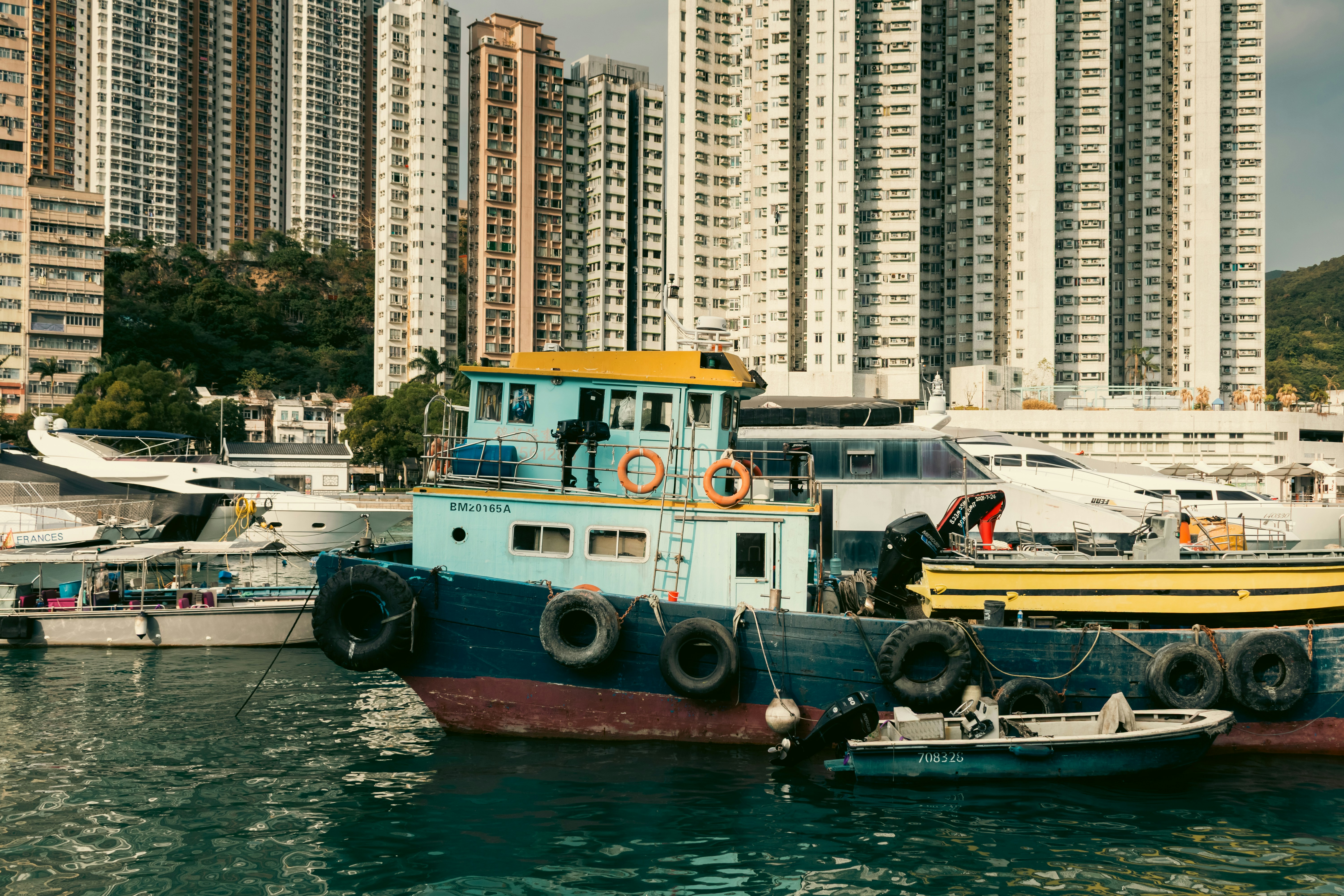 Blue Tugboat in a Quiet Marina Amid Tall Urban Dwellings