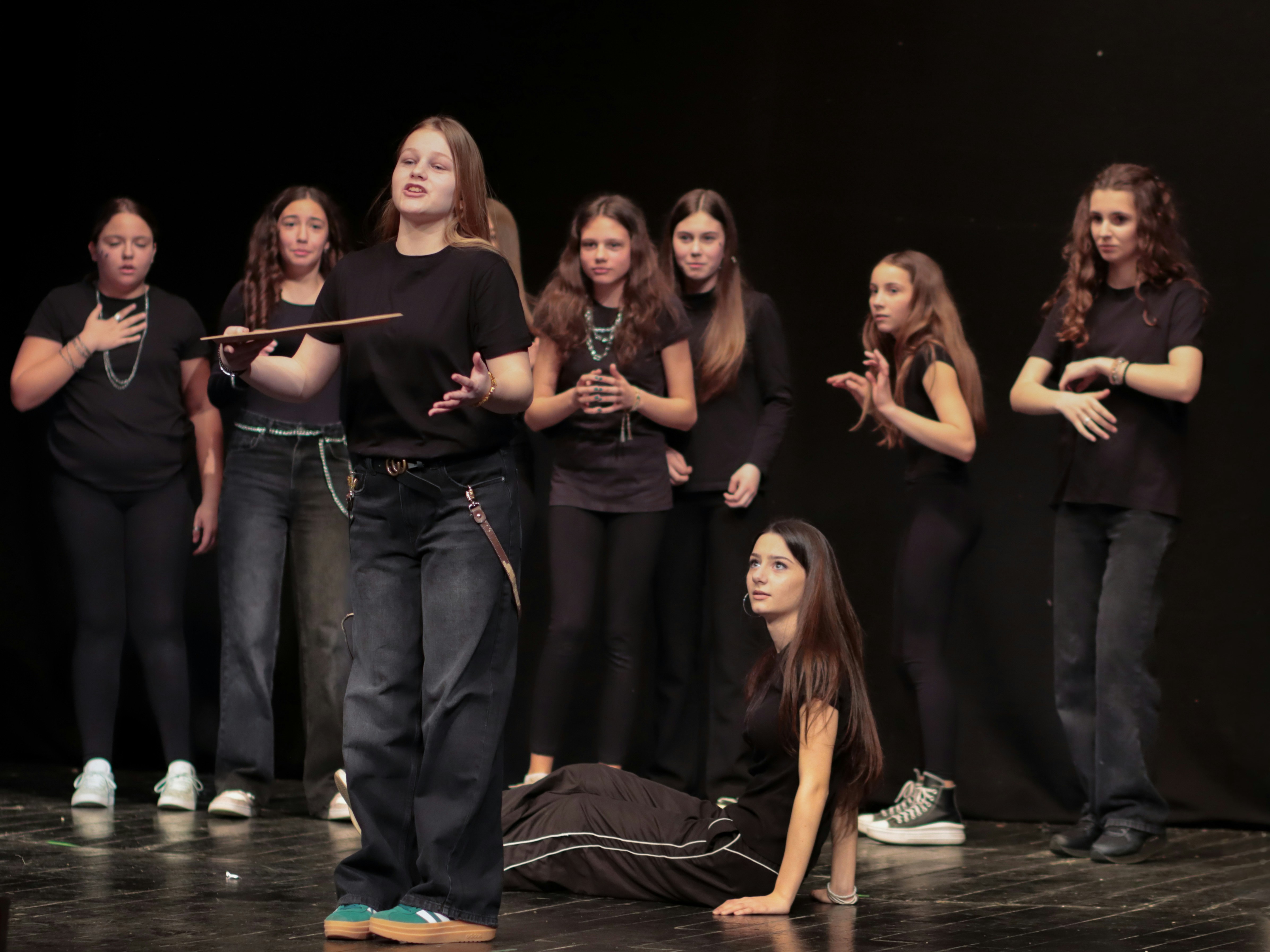Center Stage: A Vocalist Stands While Dancers Repose on Stage