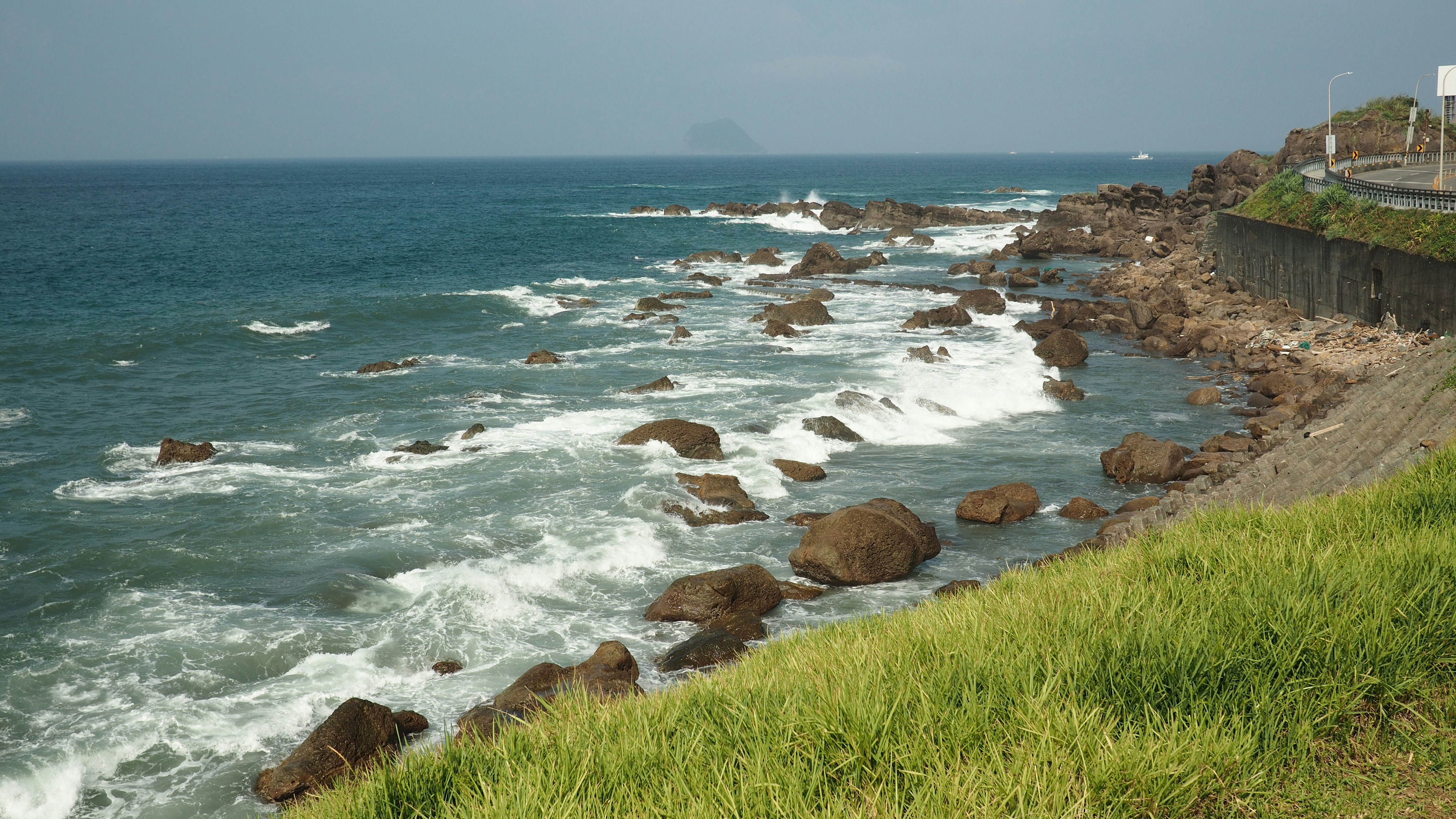 Rugged coastline under a calm sky with grassy foreground