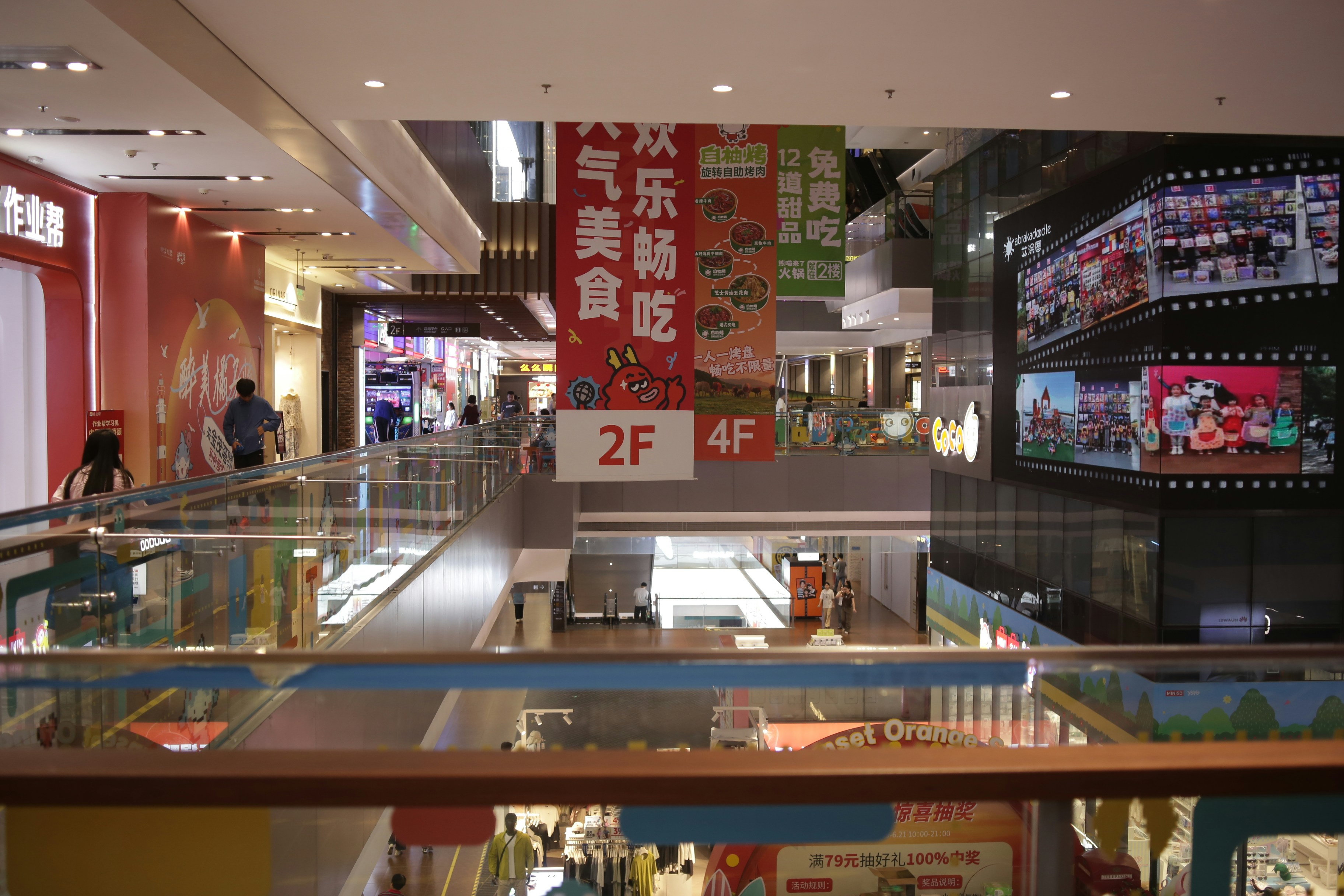 Elevated view of a bustling shopping mall atrium with vibrant banners