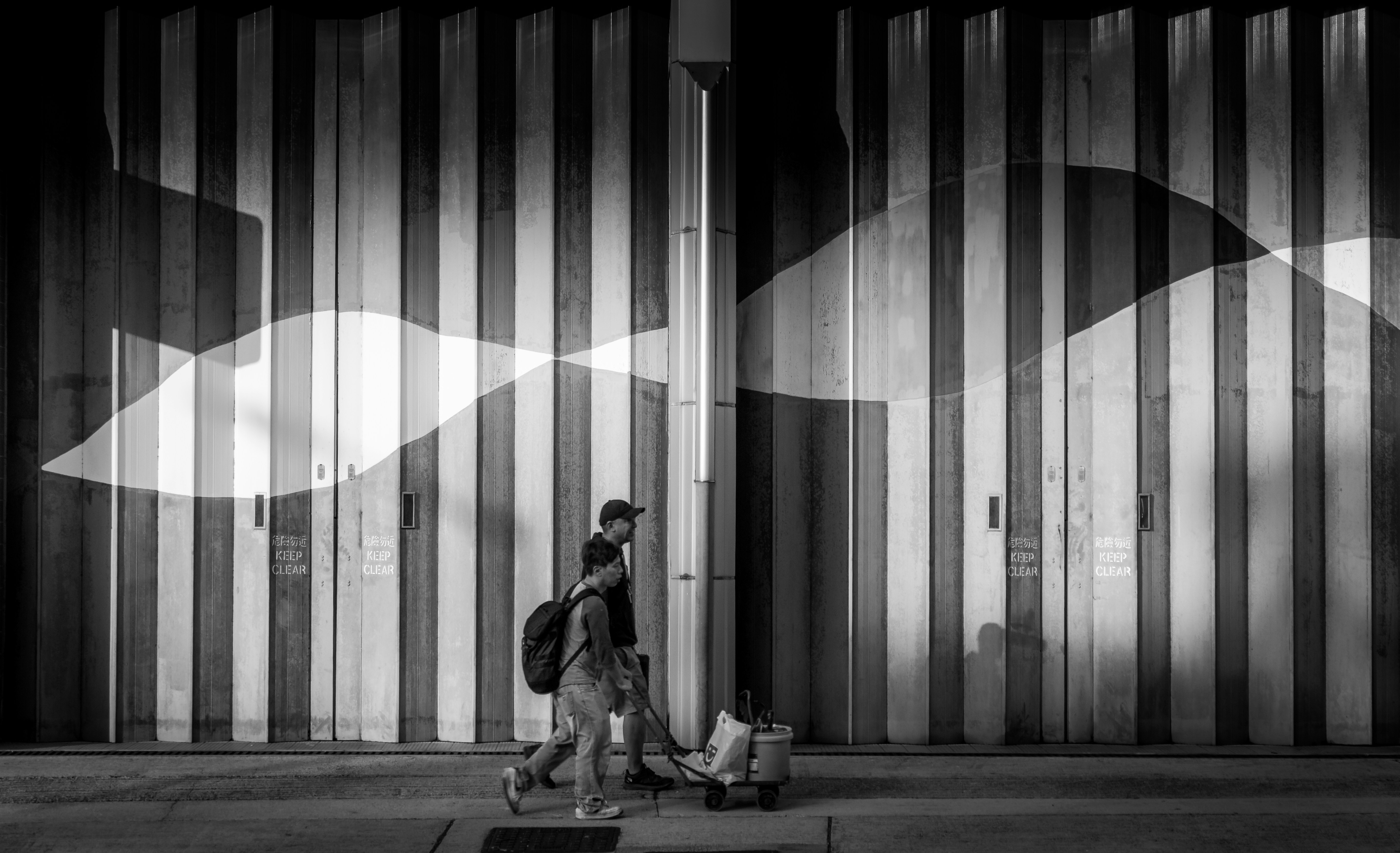 Traveler with a rolling suit: A quiet stride before the mural curtains