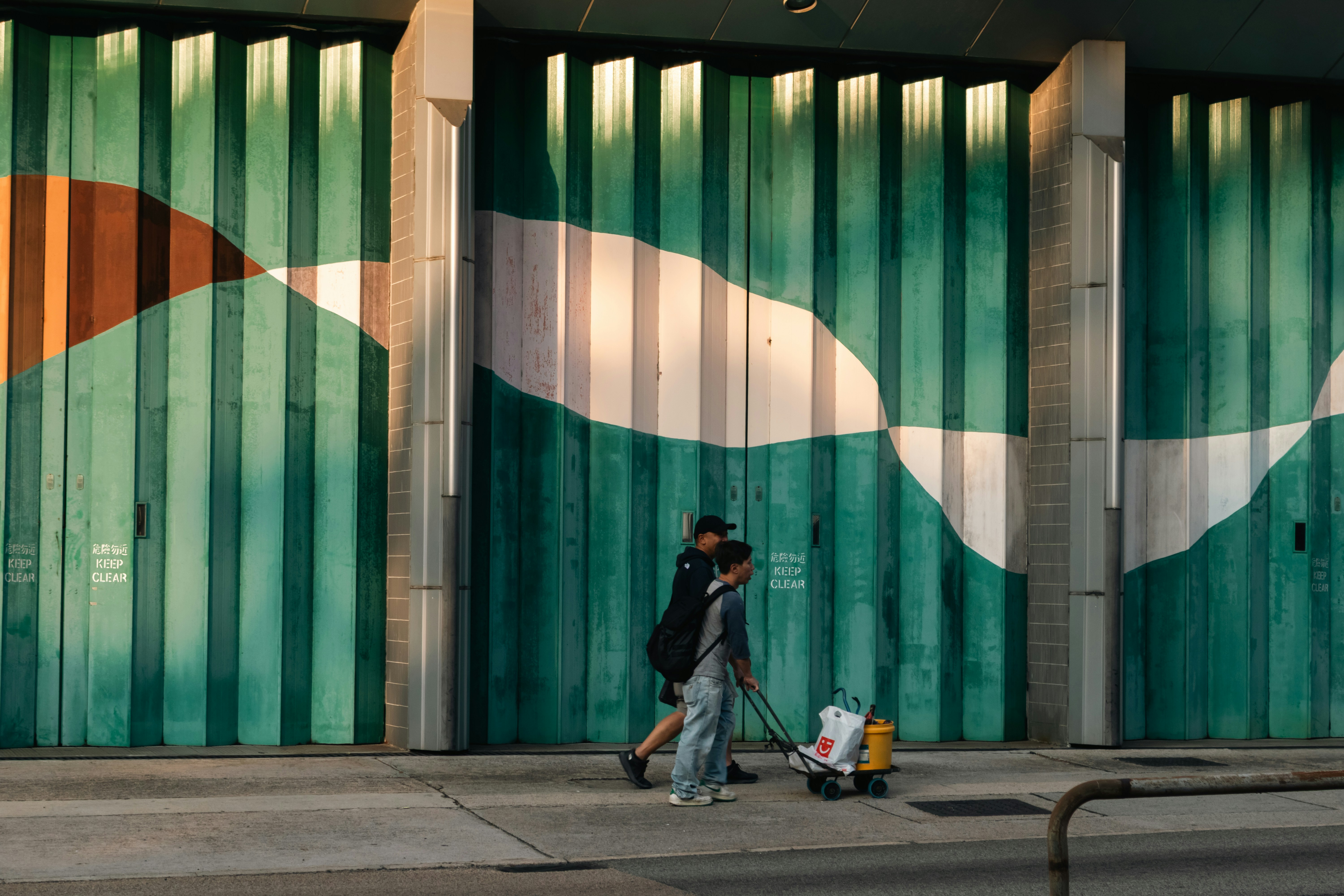 Urban Crossing: A Pair with a Trolley on a Painted Concrete Wall