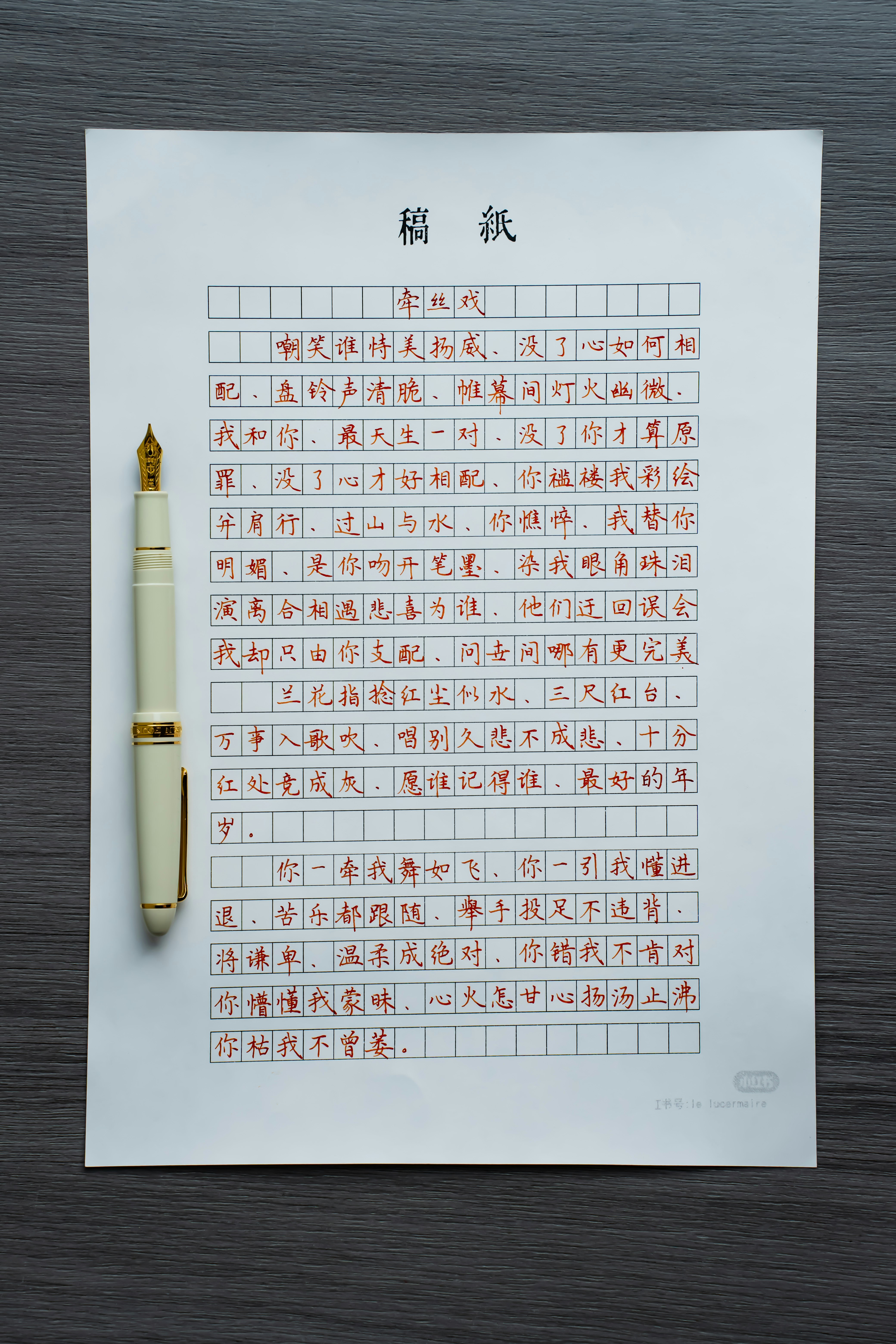 A fountain pen beside a sheet of manuscript paper with handwritten Chinese calligraphy.