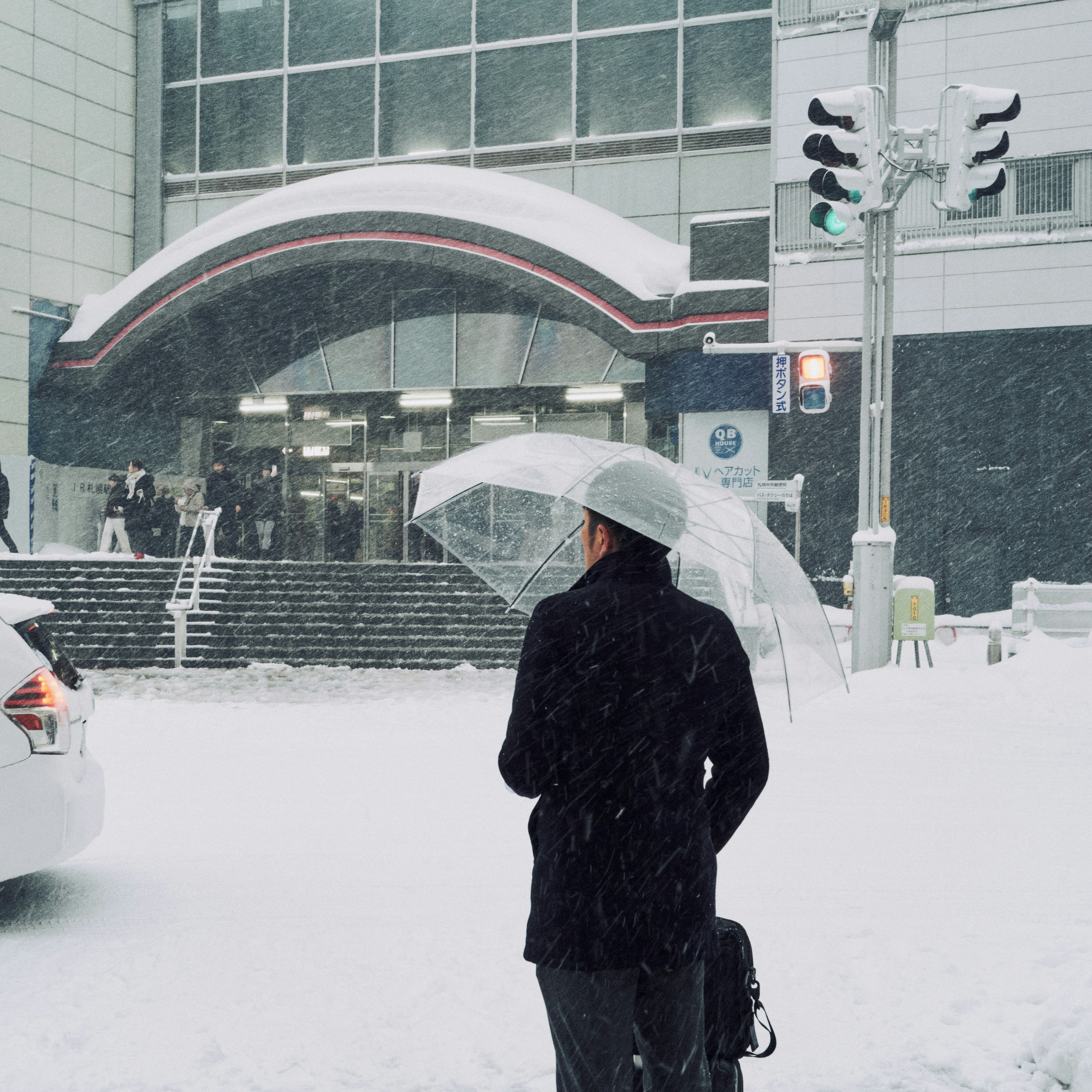 Snowy Crossing: A Traveler with an Umbrella in a City Square