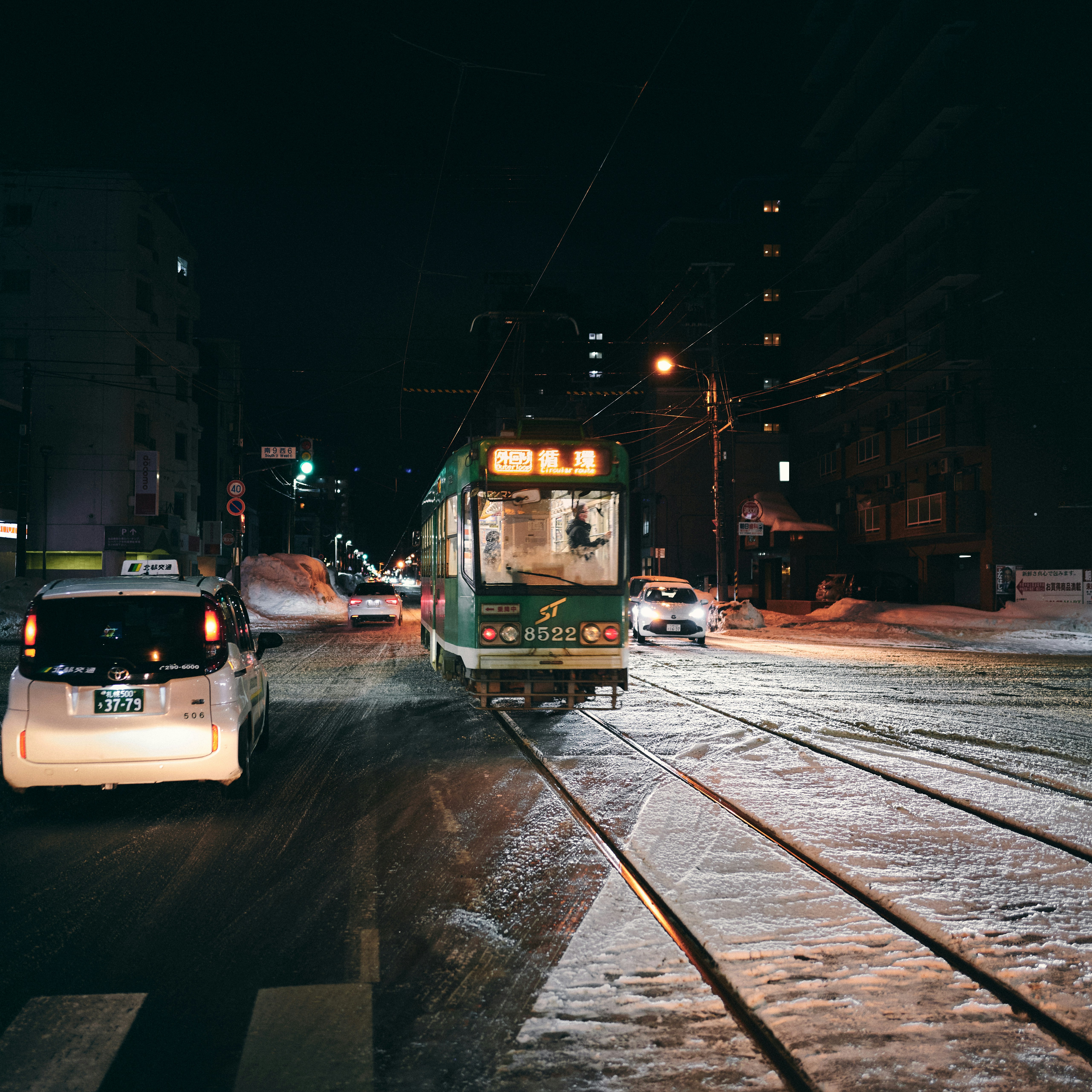 Night Streetcar: Centered on the Green Tram Slipping Through Snowlit Tracks