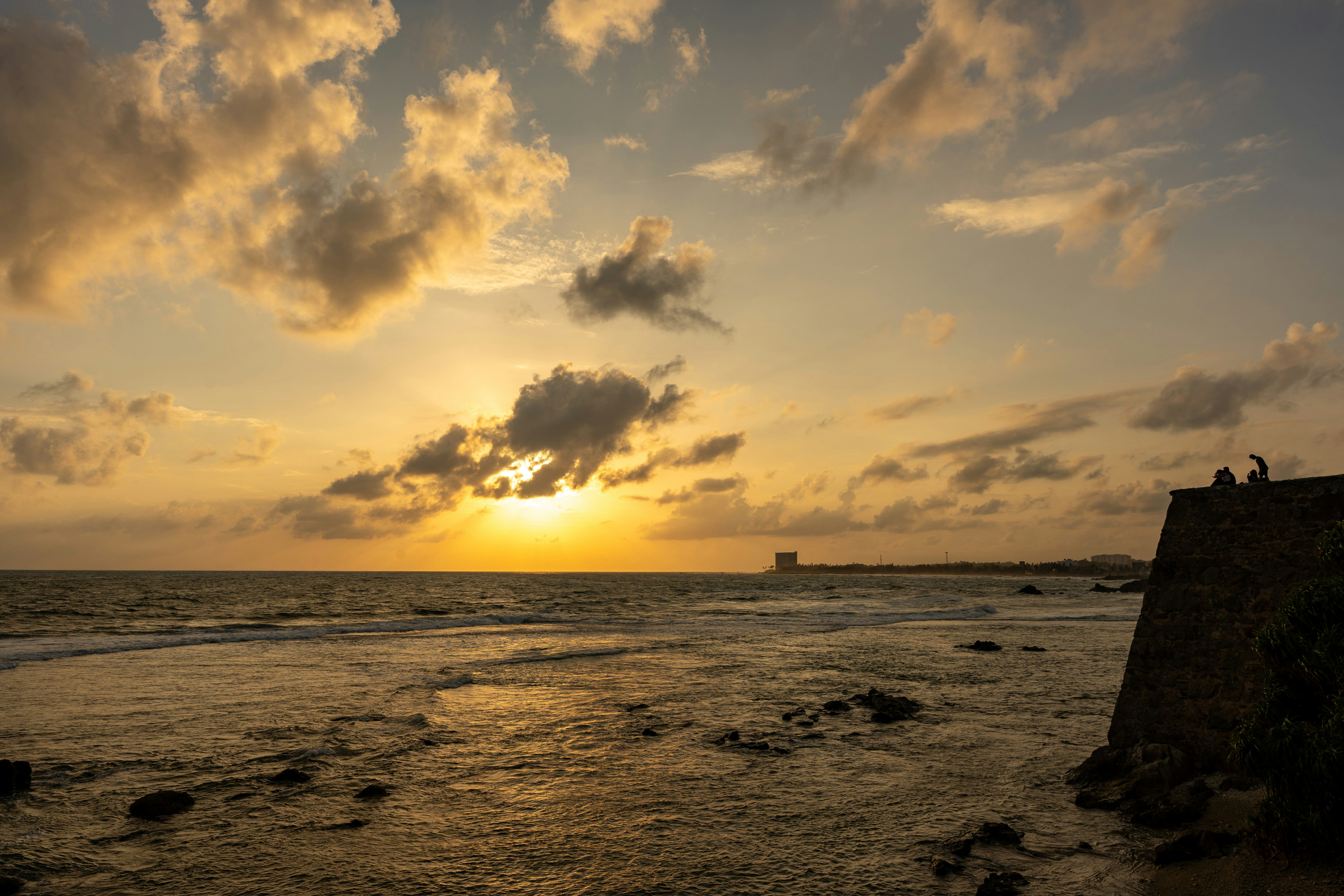 Golden Horizon Over Jagged Rocks: Sunset at the Fort Pier