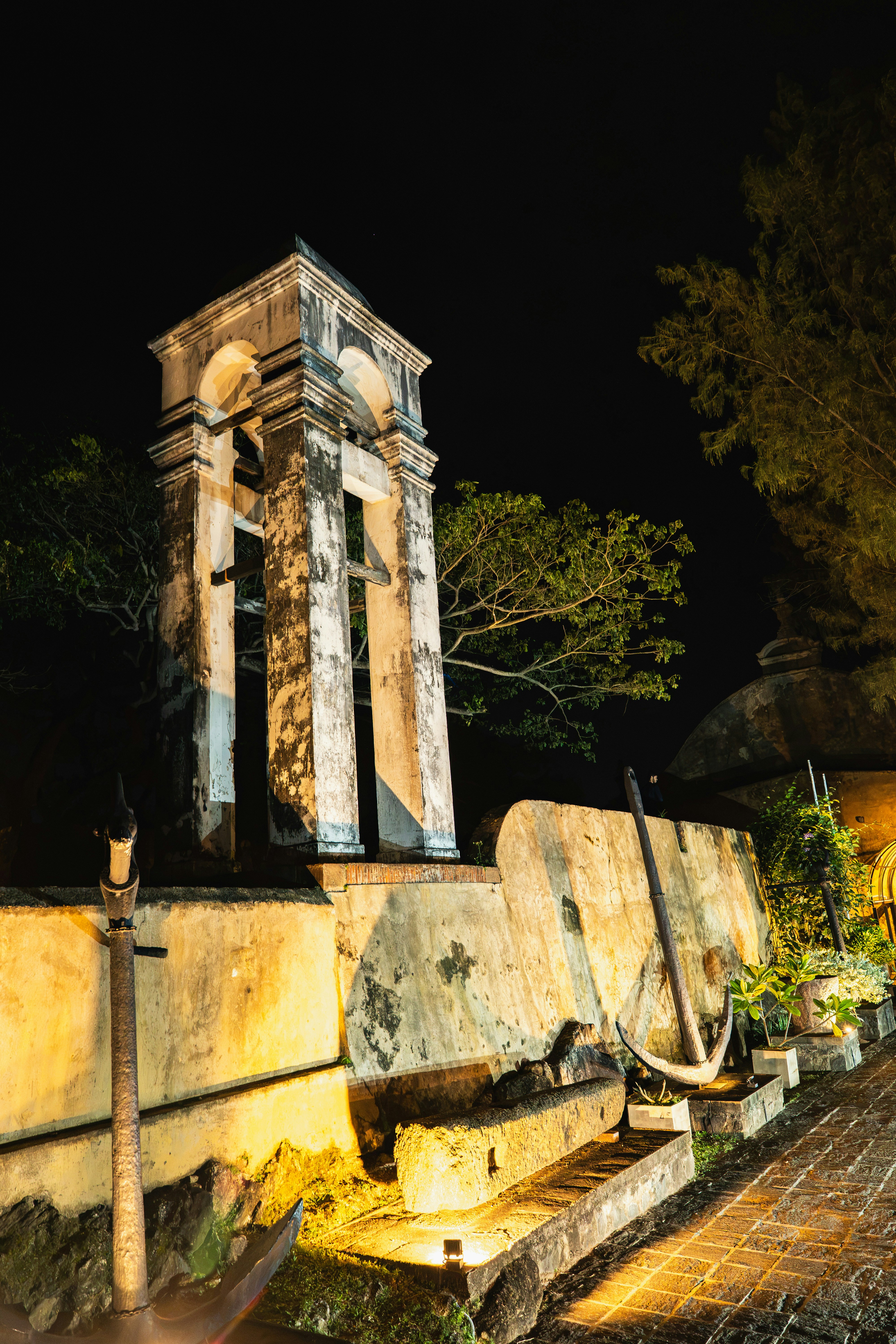 Moonlit bell tower over weathered stone and garden path