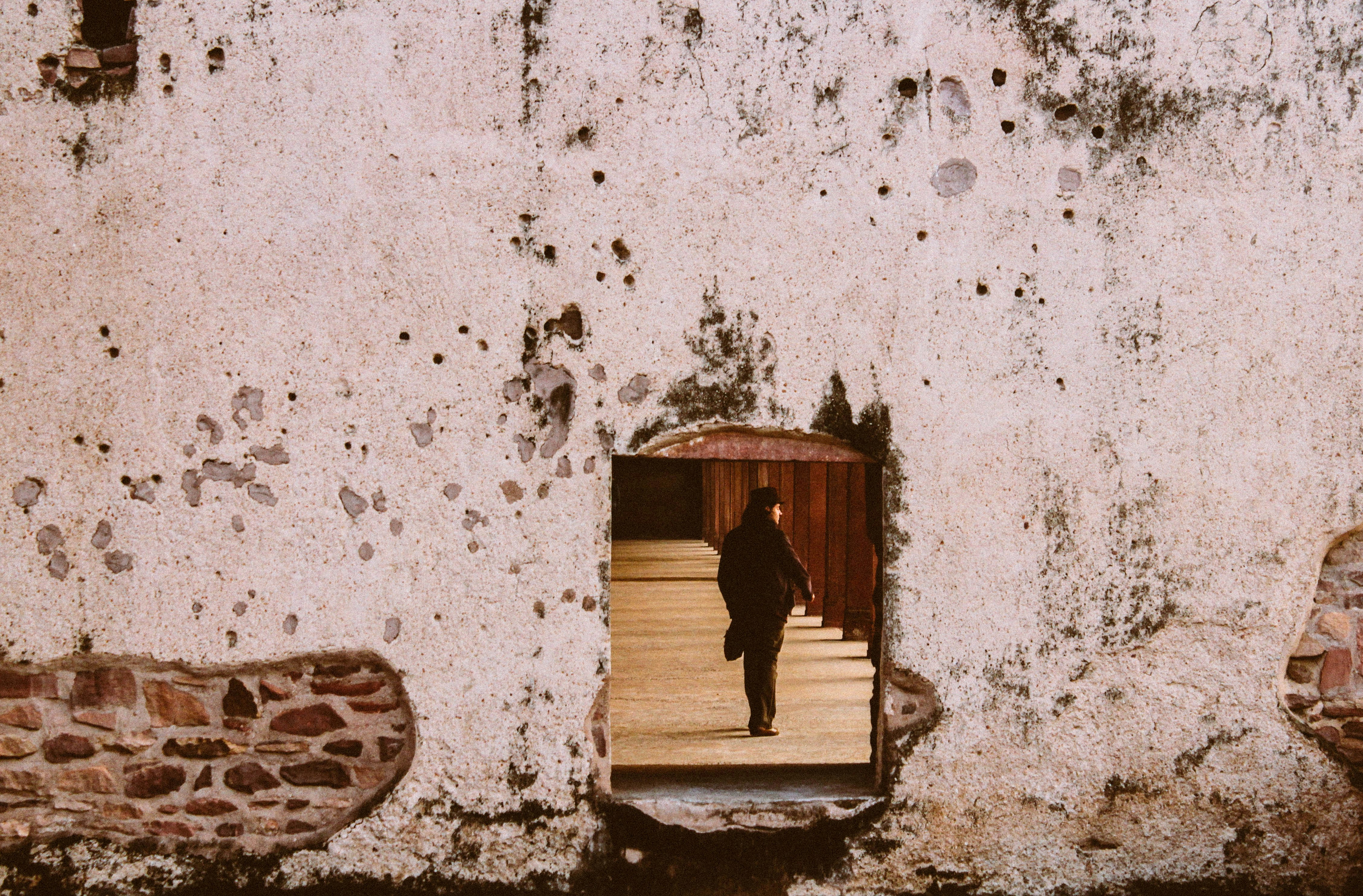 Through the Walled Frame: A Lone Visitor in a Weathered Corridor