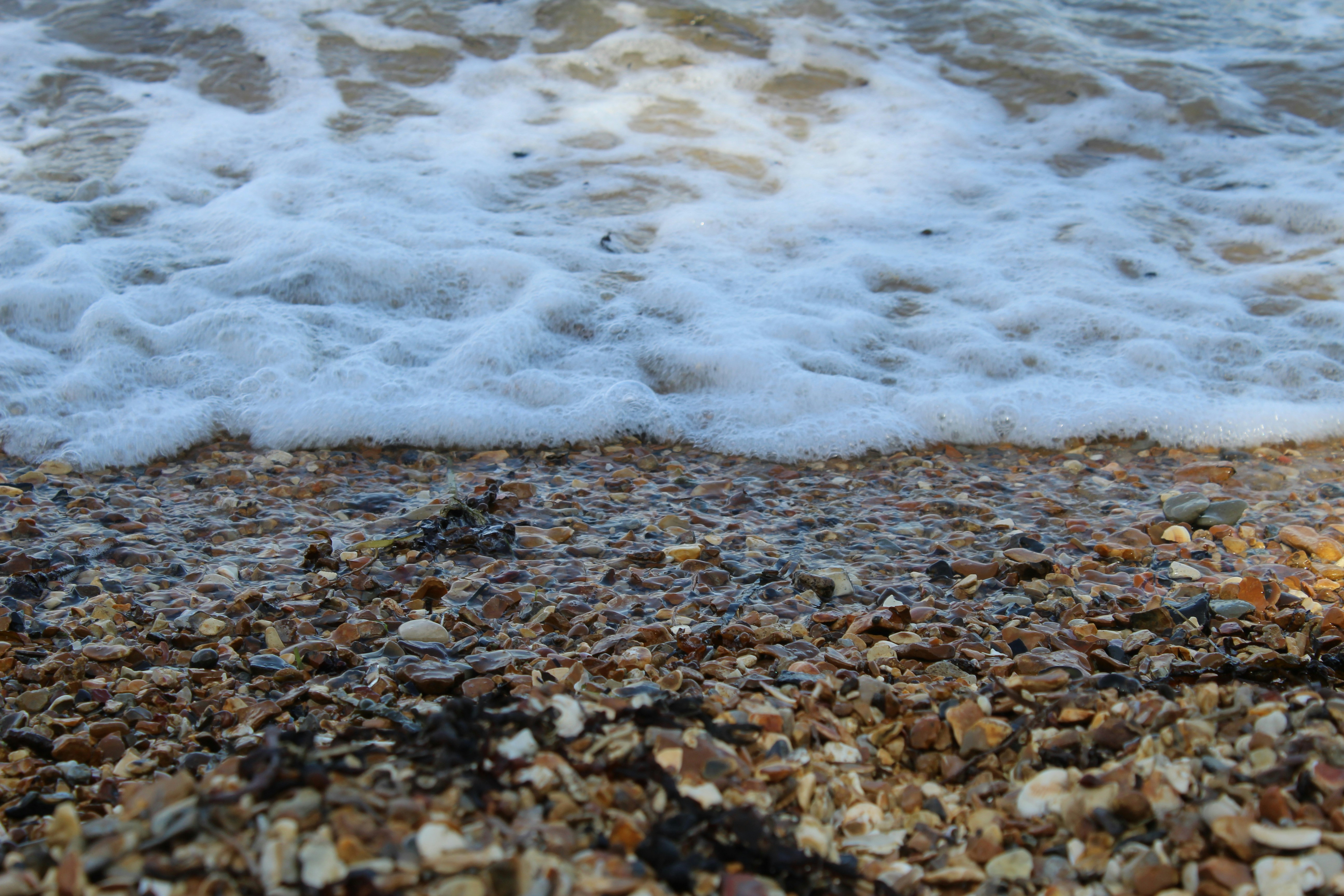 Foamy Shoreline Over Pebbles at Dusk