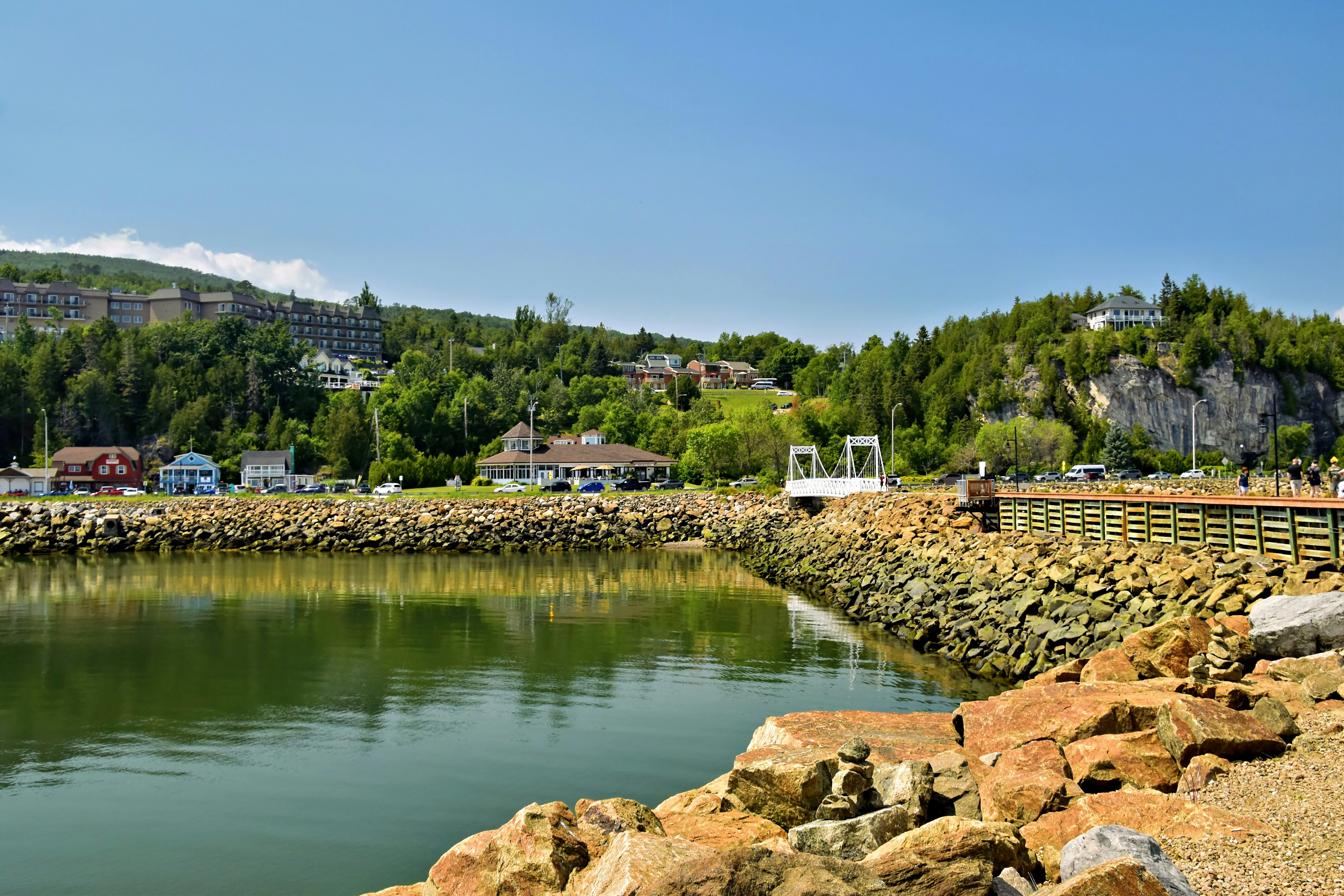 Harbor Edge: Quiet shoreline with rocky breakwater and hillside village