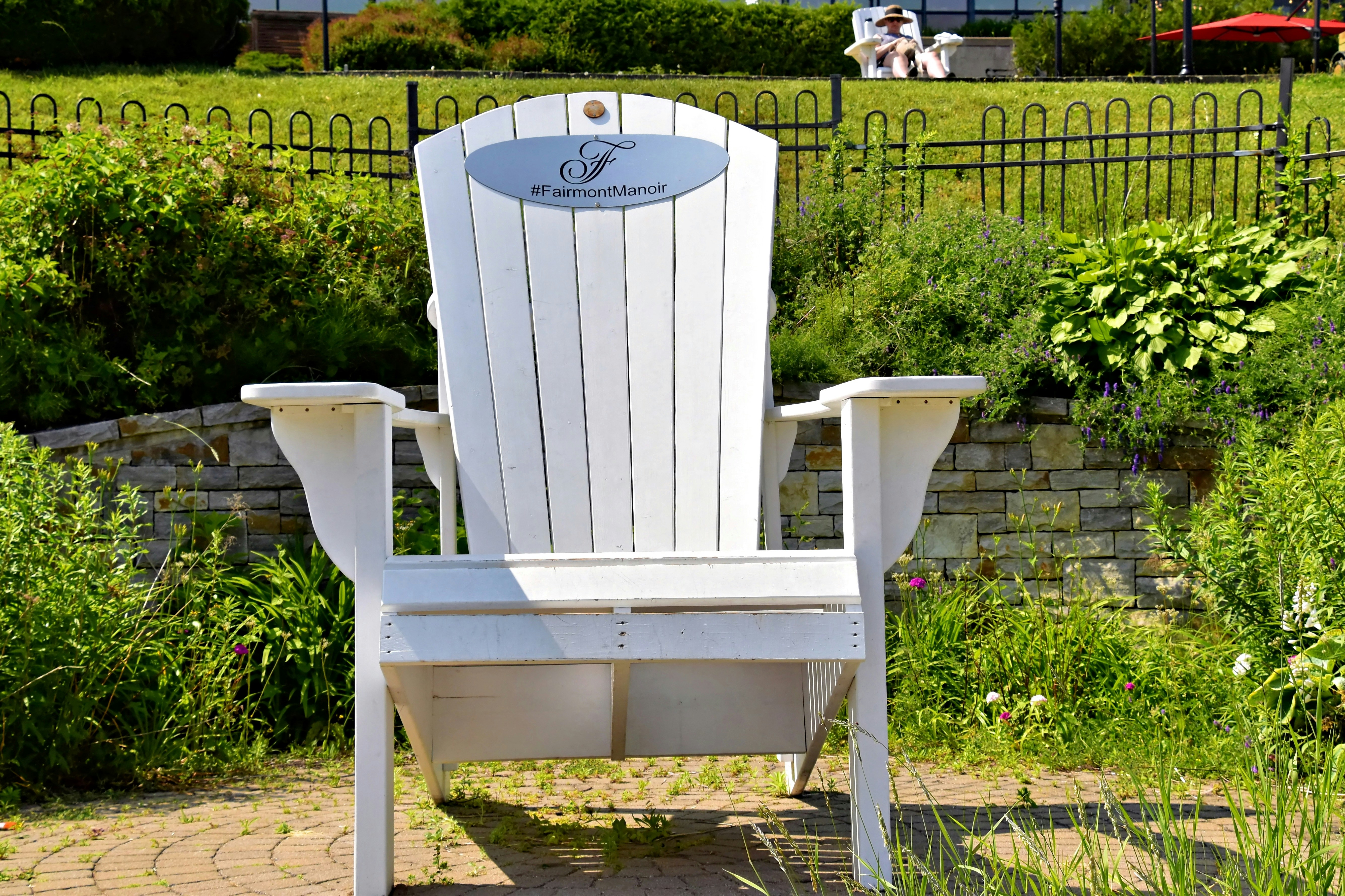 A Quiet Park Bench Reigns: White Adirondack Chair Under Sunlit Garden