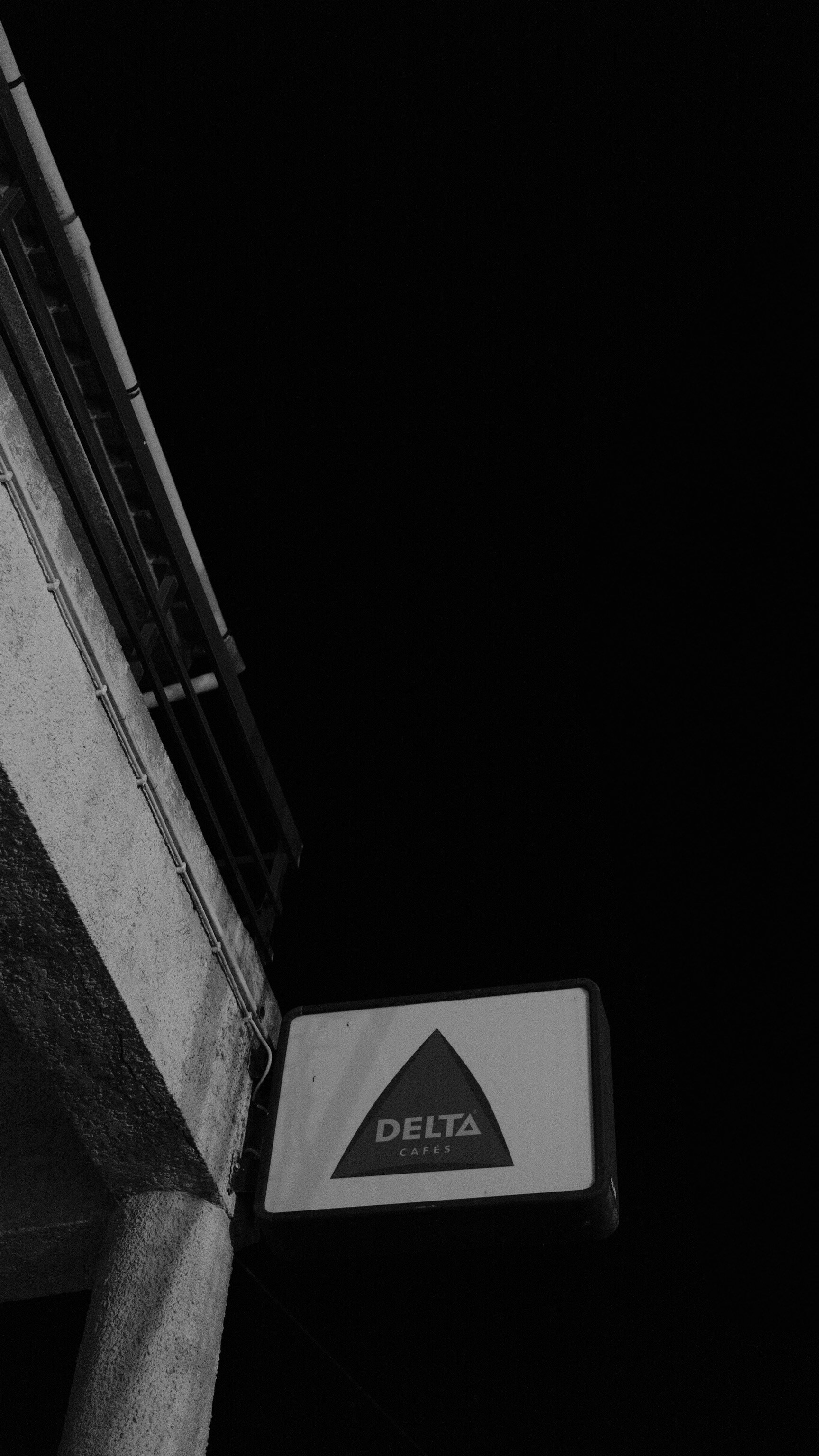 Delta sign at night: a lone beacon on a stark façade