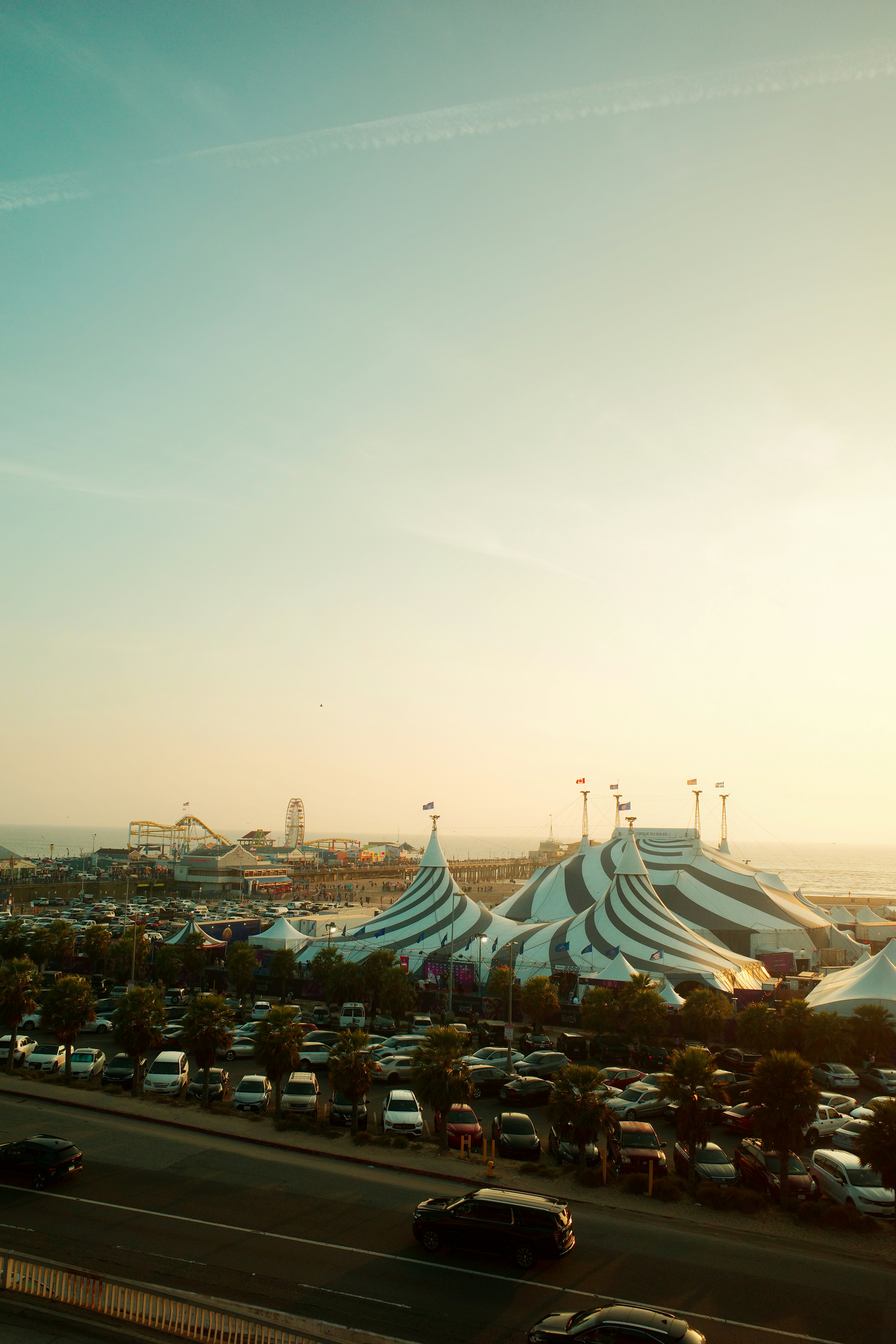 Sunlit Coastline Fairground: Tents, Cars, and Distant Rides