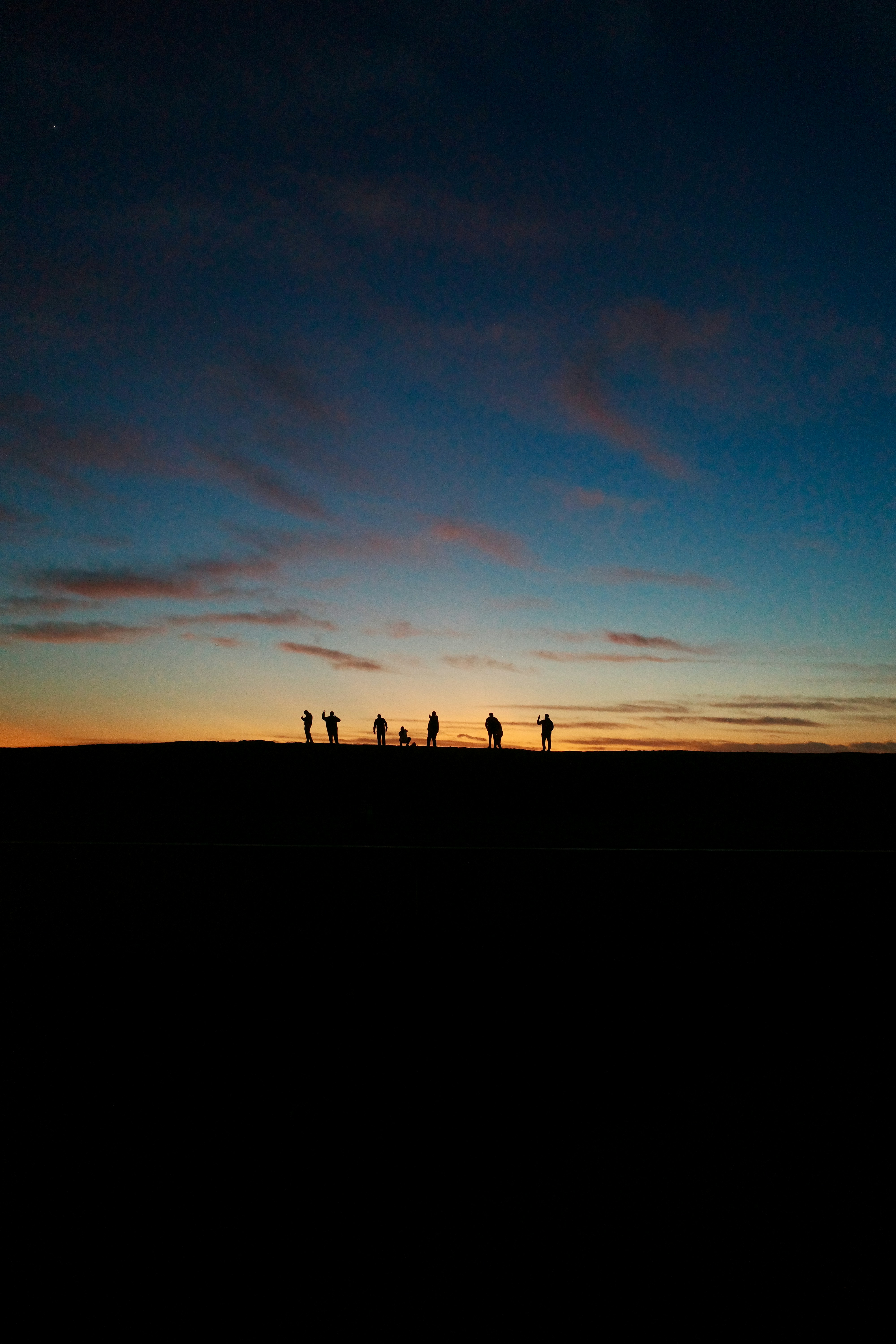 Silhouettes at Dusky Horizon: A Distant Row of Figures on the Rim