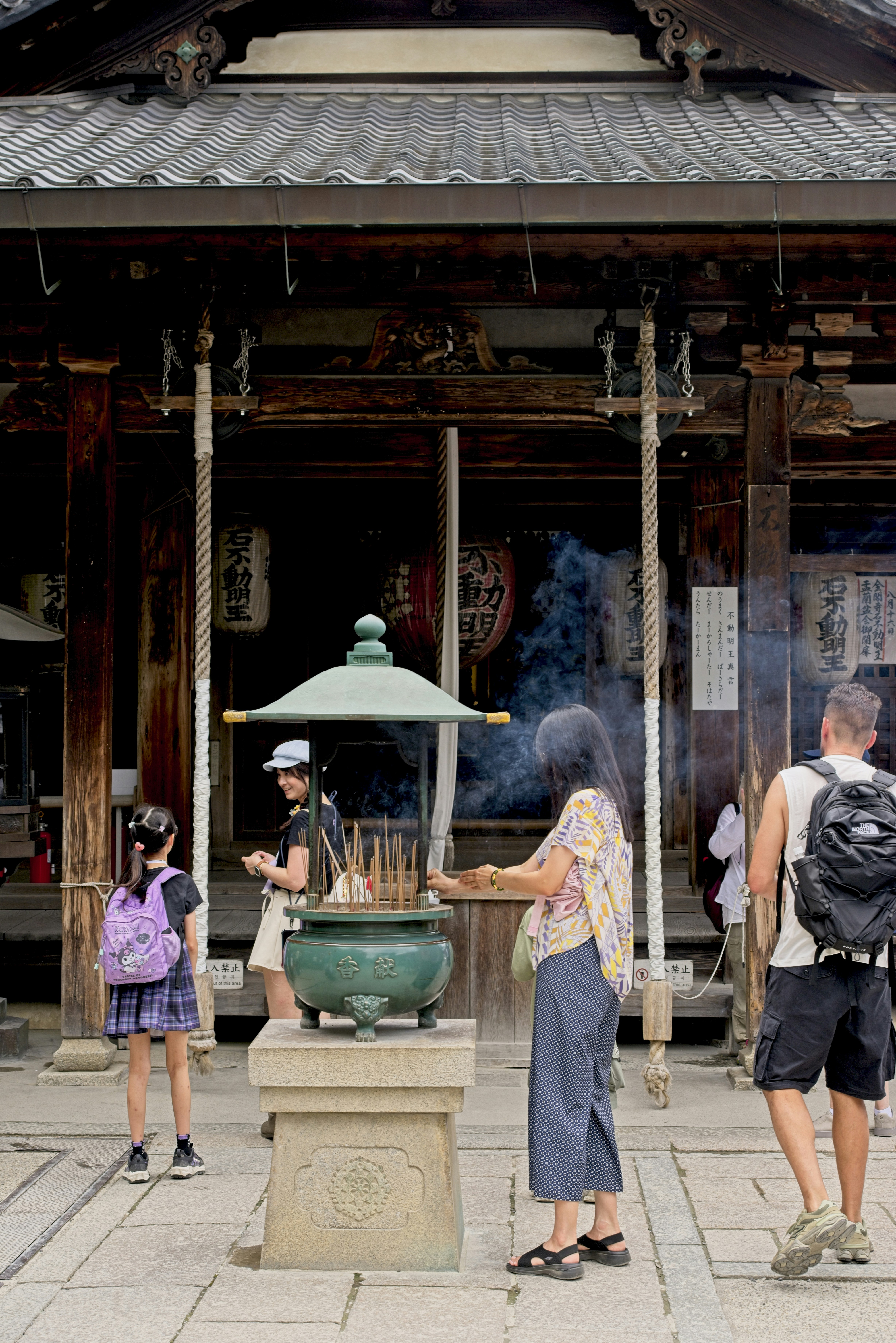 Rituals by the incense: visitors in a Shinto temple courtyard