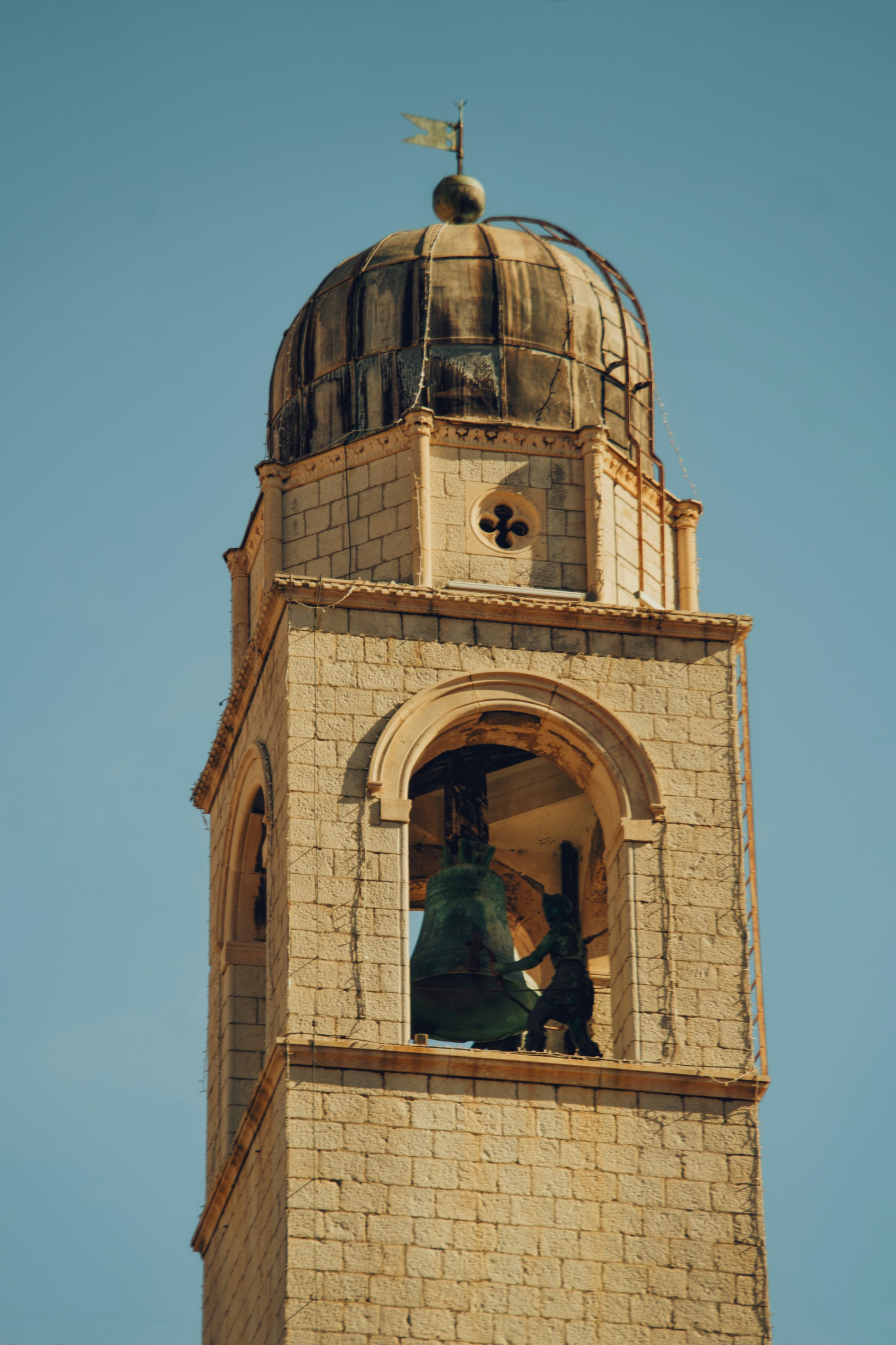 Stone Bell Tower with Open Archway and Bronze Bell
