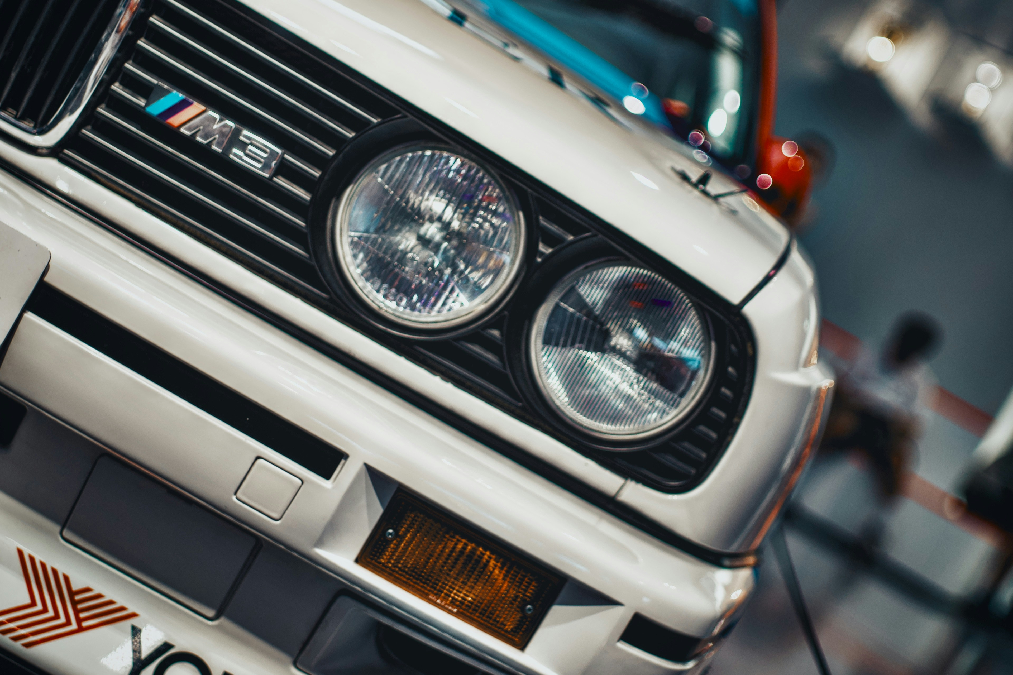 Close-up of a vintage M badge and dual headlights on a white classic BMW