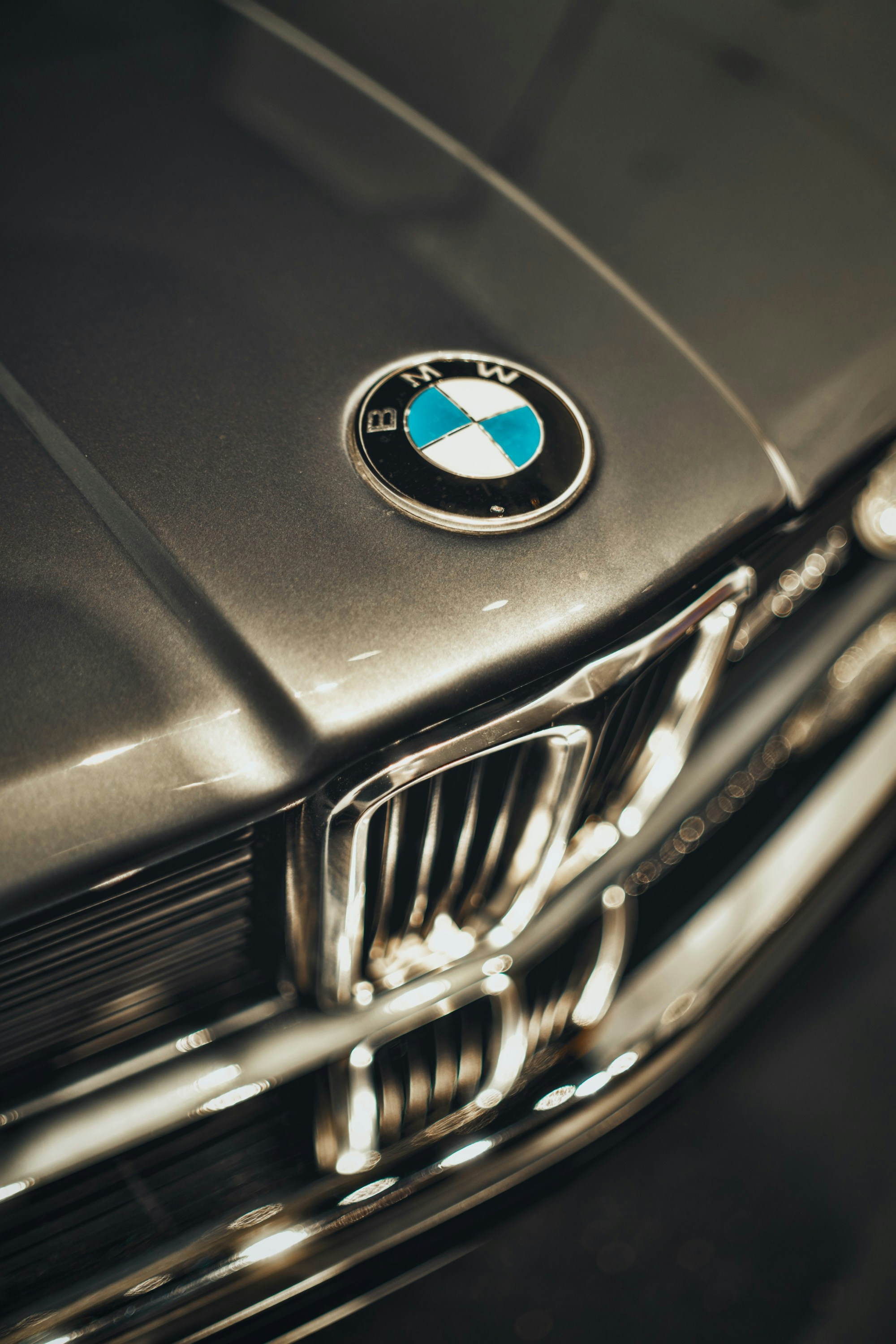 BMW badge on vintage car hood: chrome grille and emblem close-up