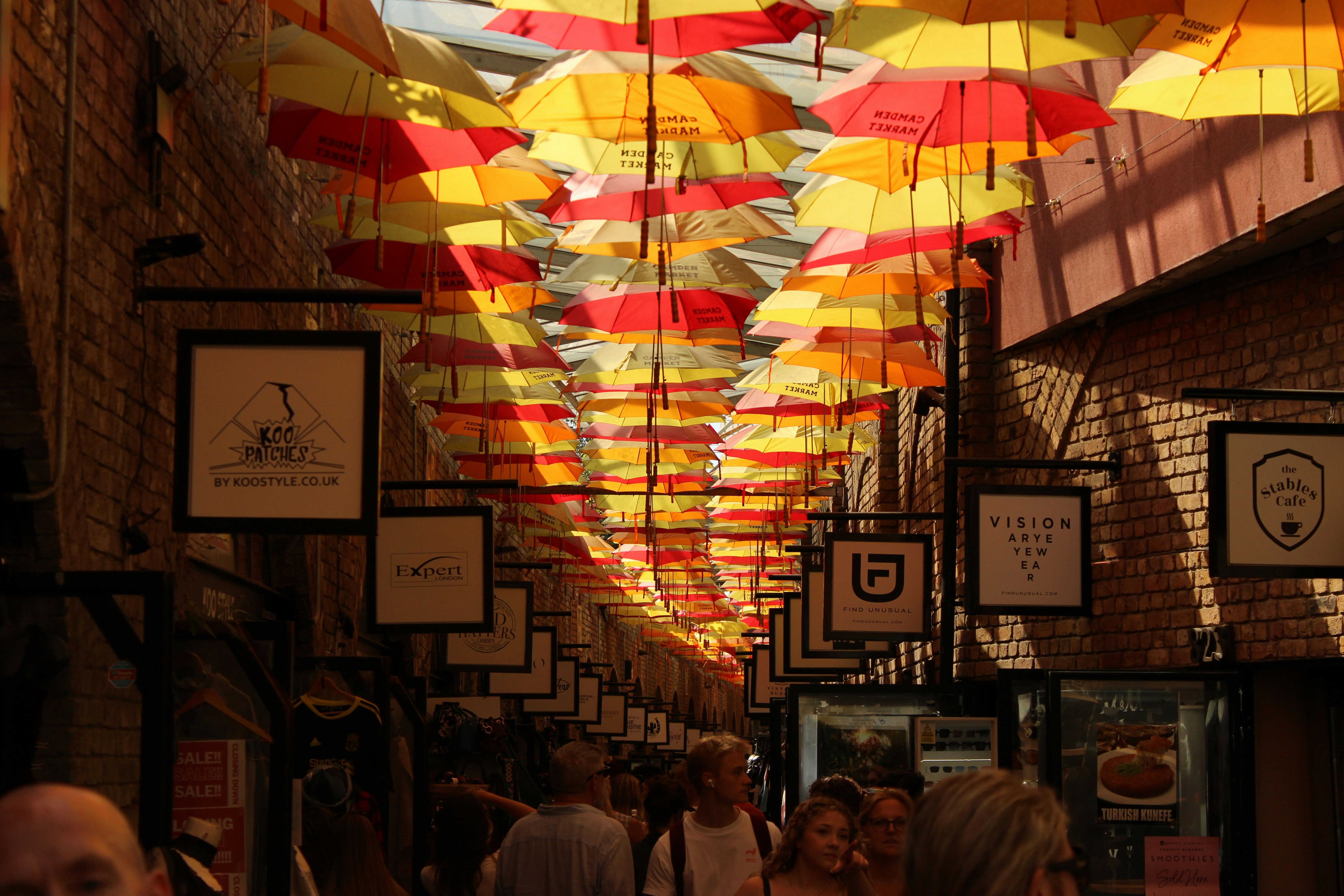 Colorful Corridor: A Canopy of Umbrellas Over a Busy Brick Alley