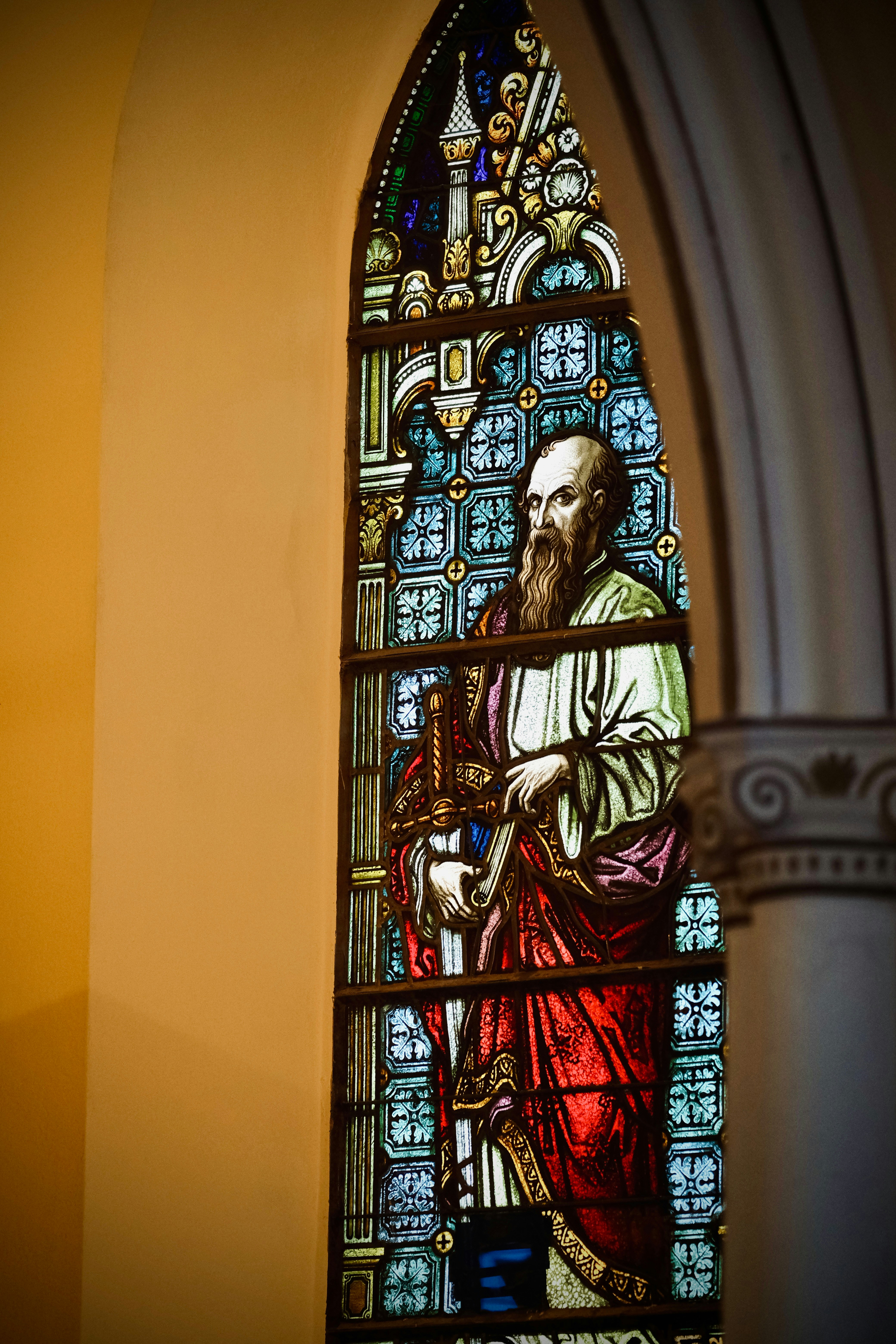 Stained Glass Sentinel: Portrait of a Bearded Saint Through a Church Arch