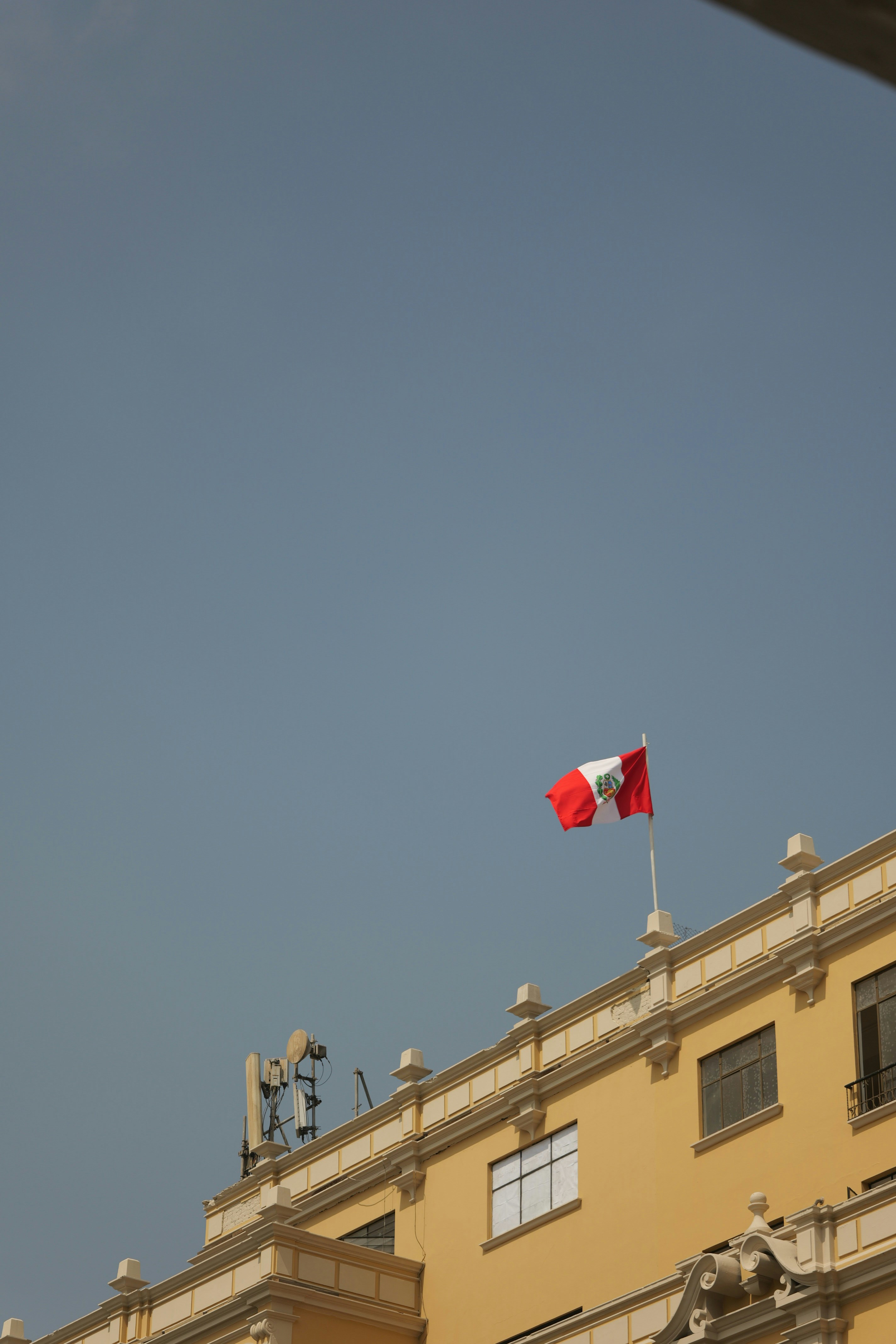 Flag Over Yellow Facade: A Government House Quietly Flags the Sky