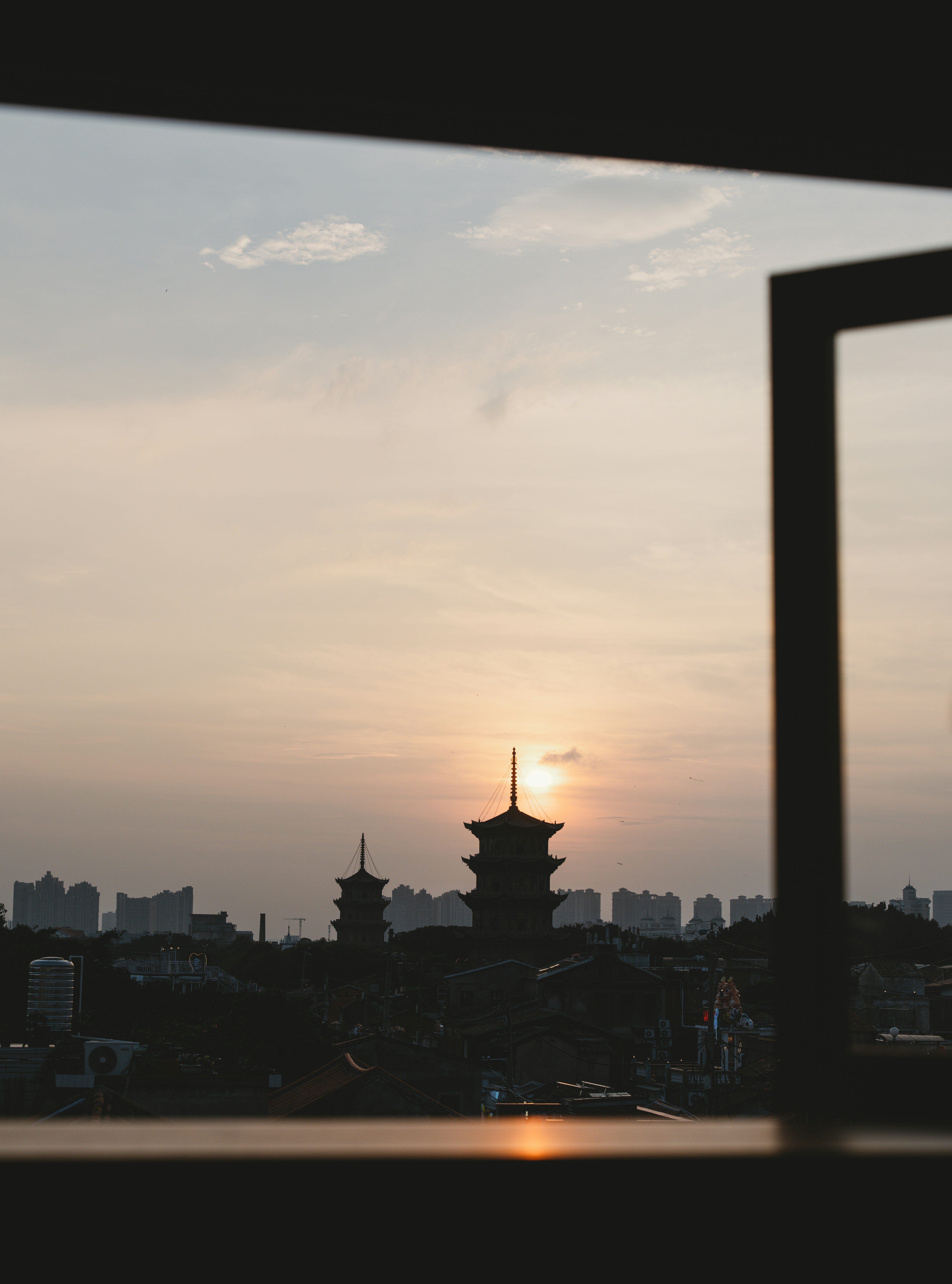Sunset Over Ancient Silhouettes: A Framed Cityscape Through a Window