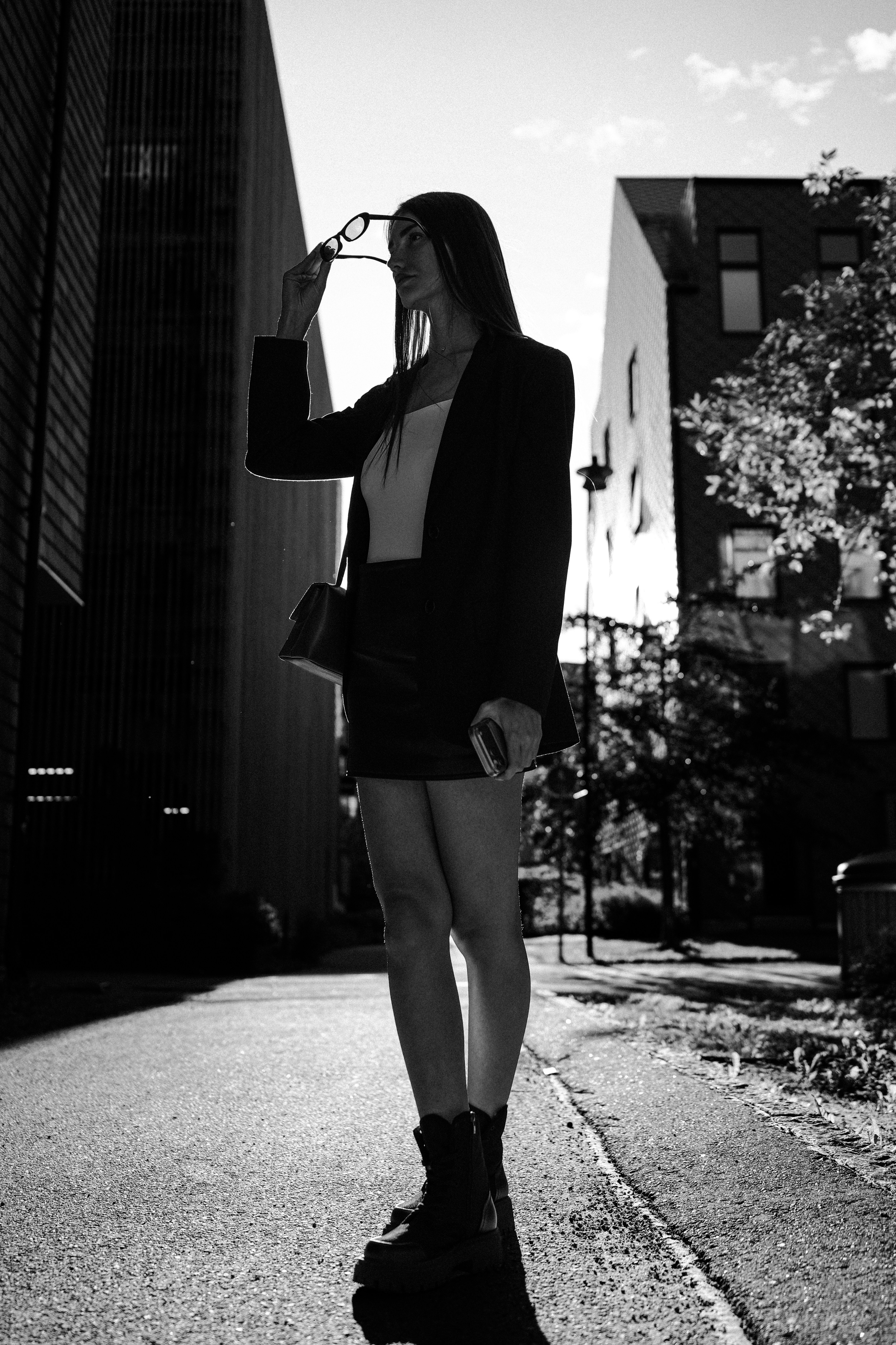 City chic: a shadowed silhouette adjusting sunglasses in urban afternoon