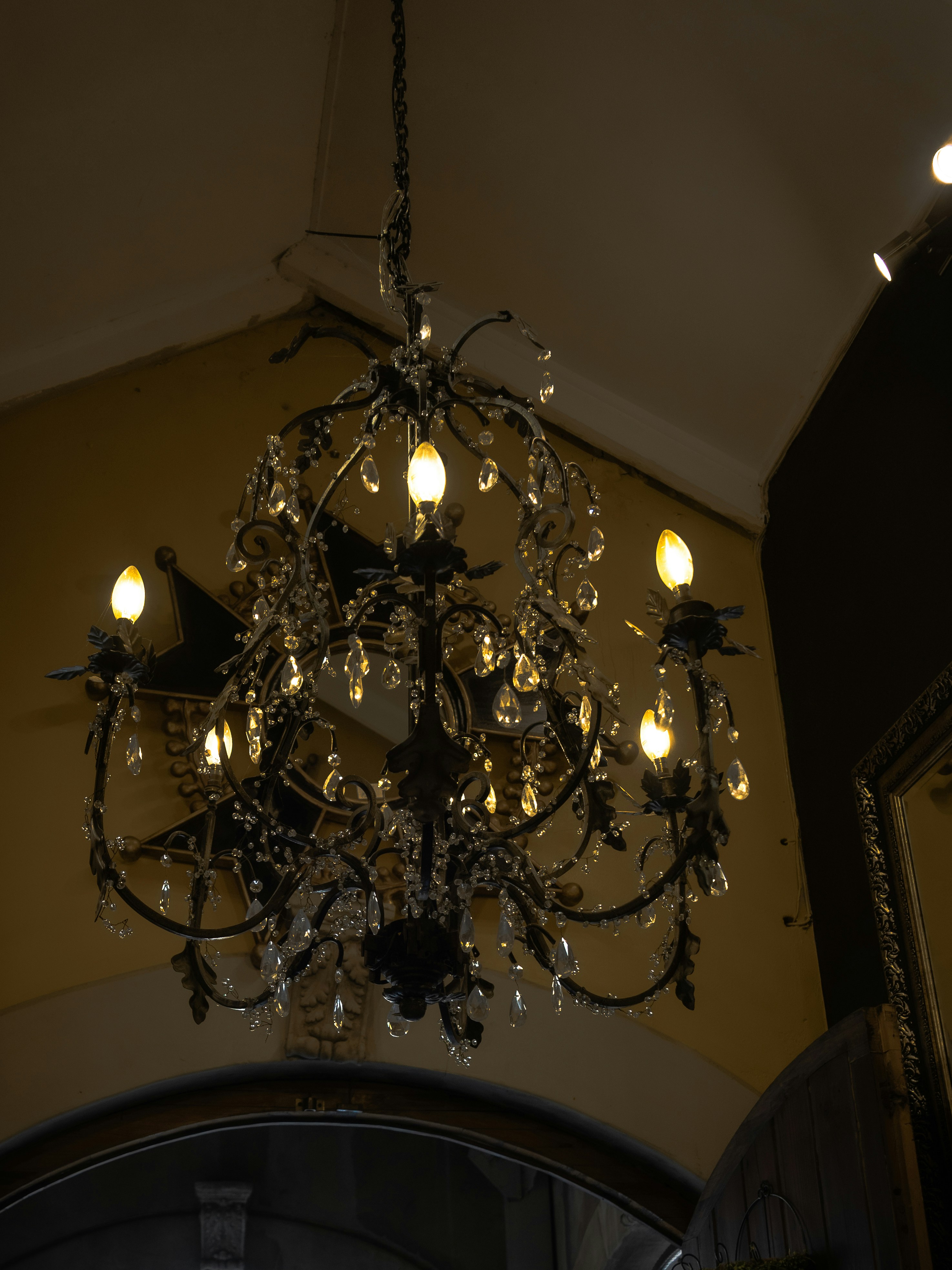 Crystal chandelier glowing in a moody indoor foyer