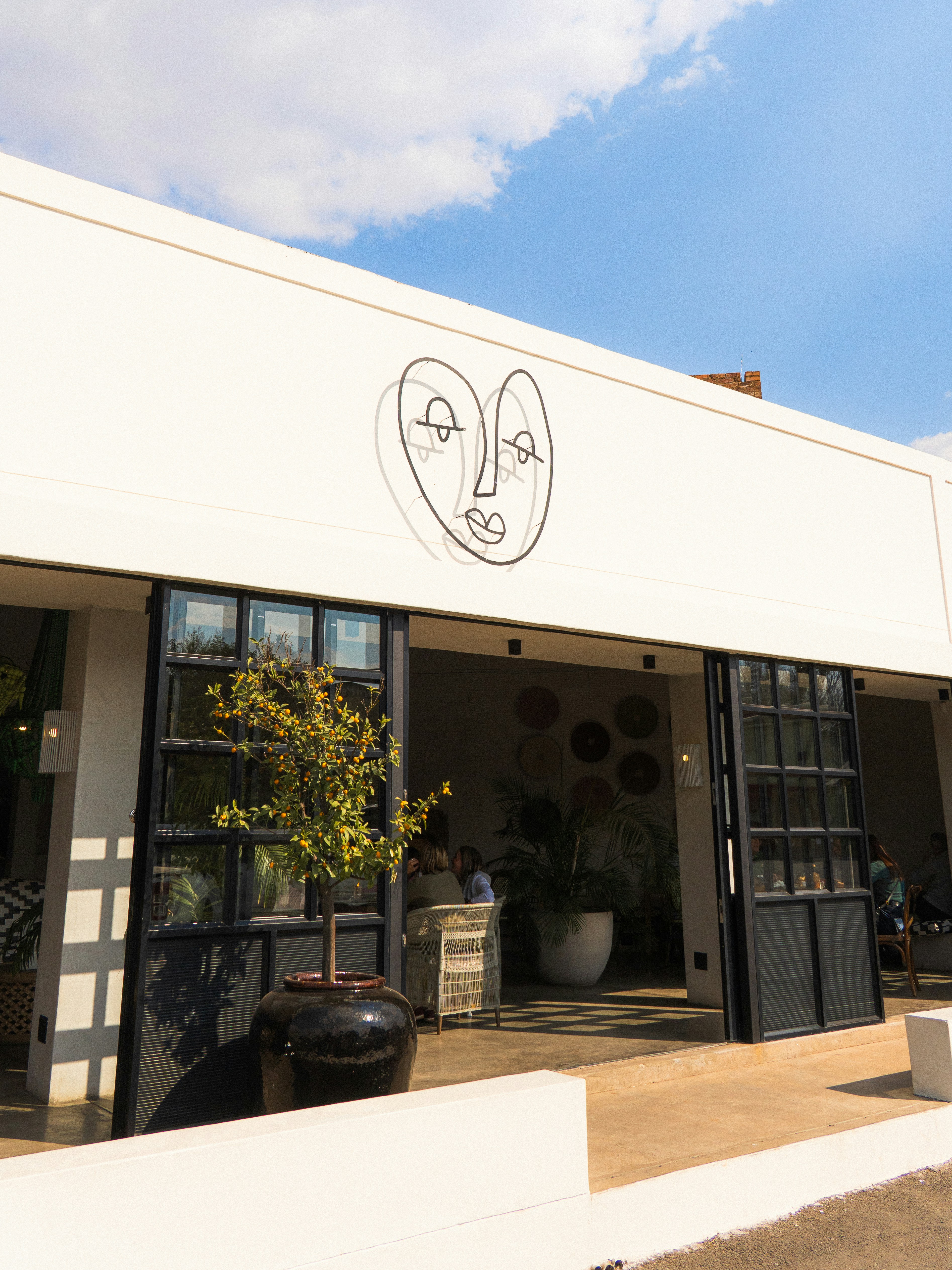 Minimal Modern Café: Open Doors, Potted Tree, and Artful Logo