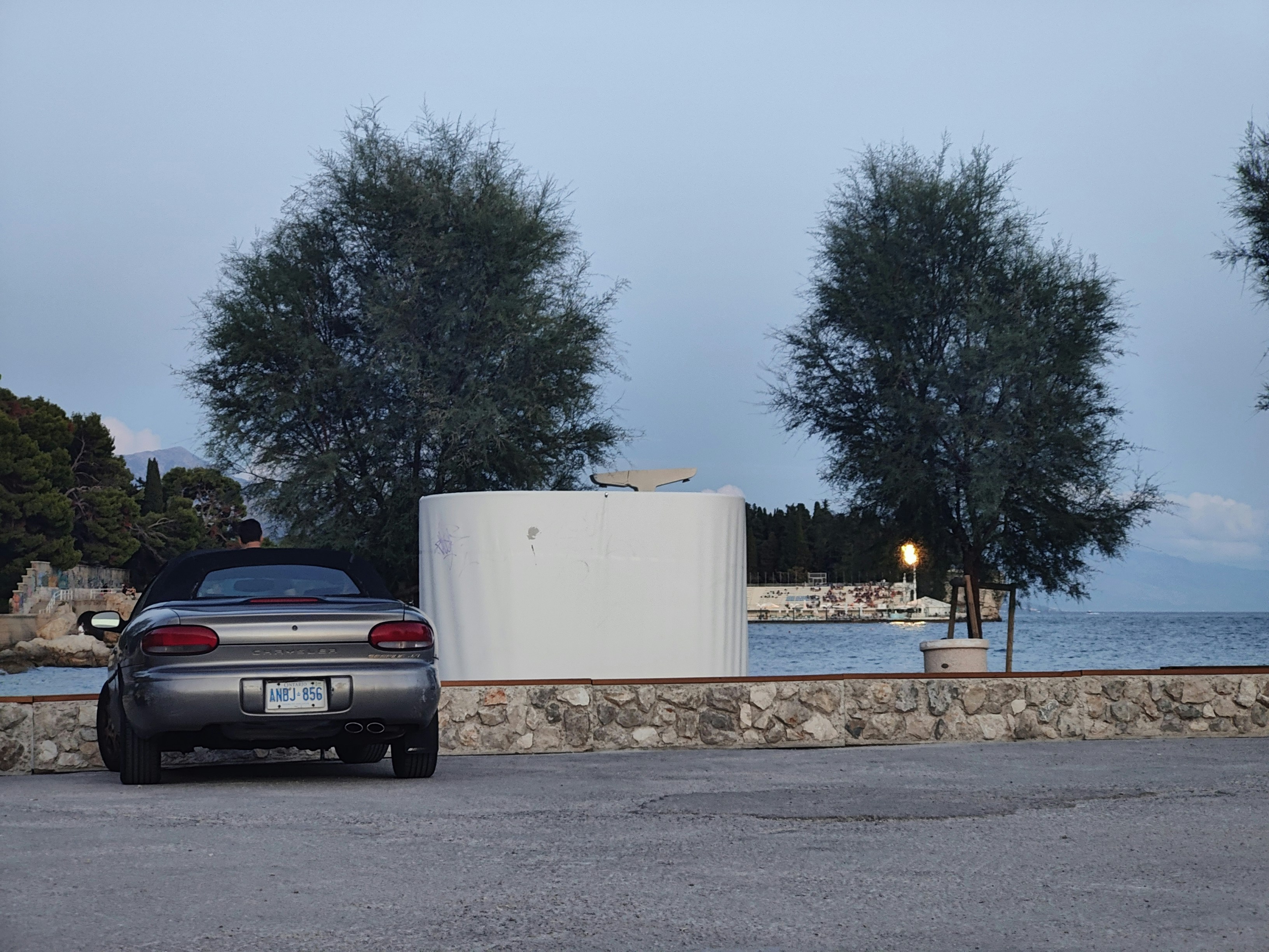 Muted Coastal Parking: A Silver Convertible by the Sea Wall