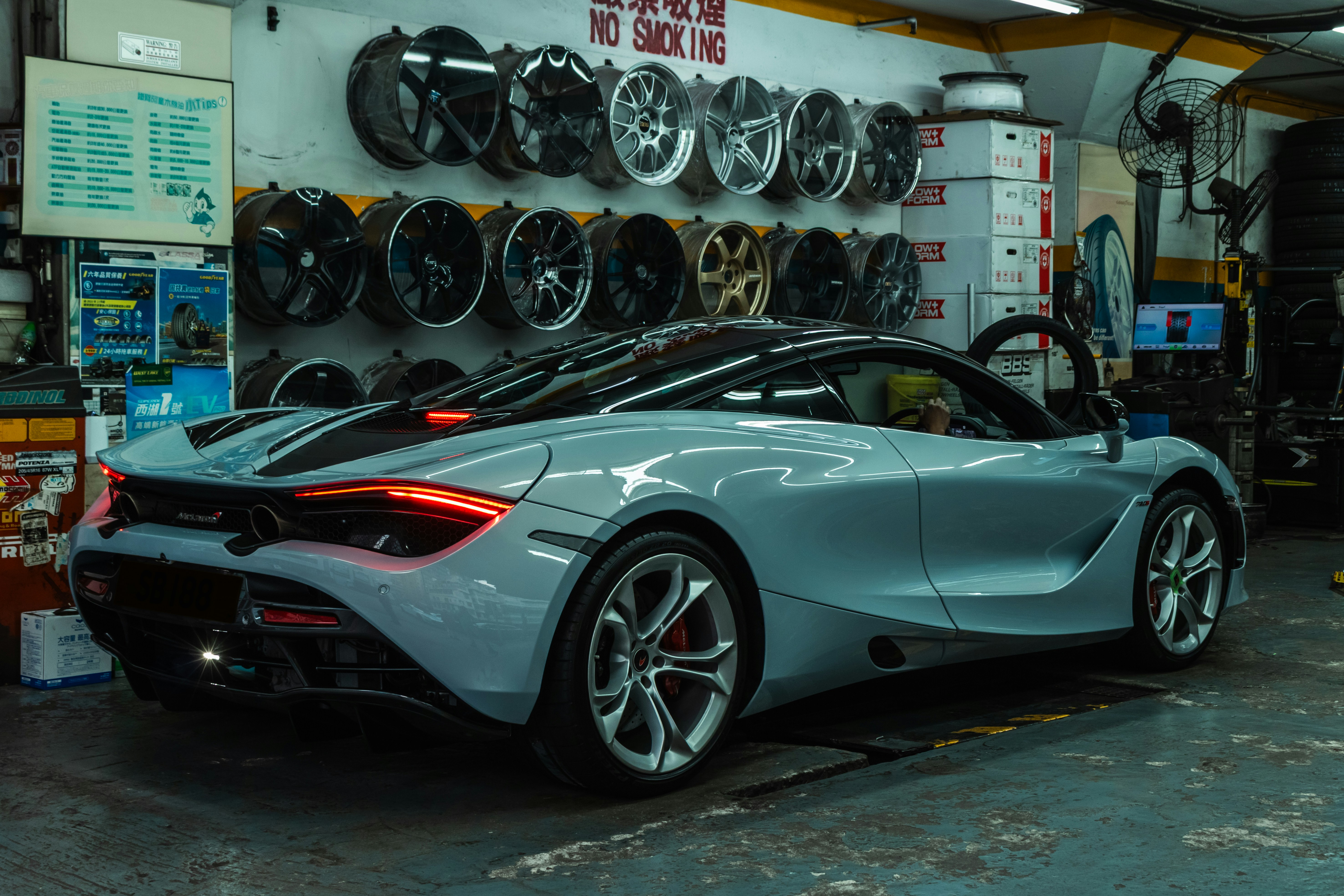 Cream-blue Mclaren in a tire workshop under cool workshop lighting