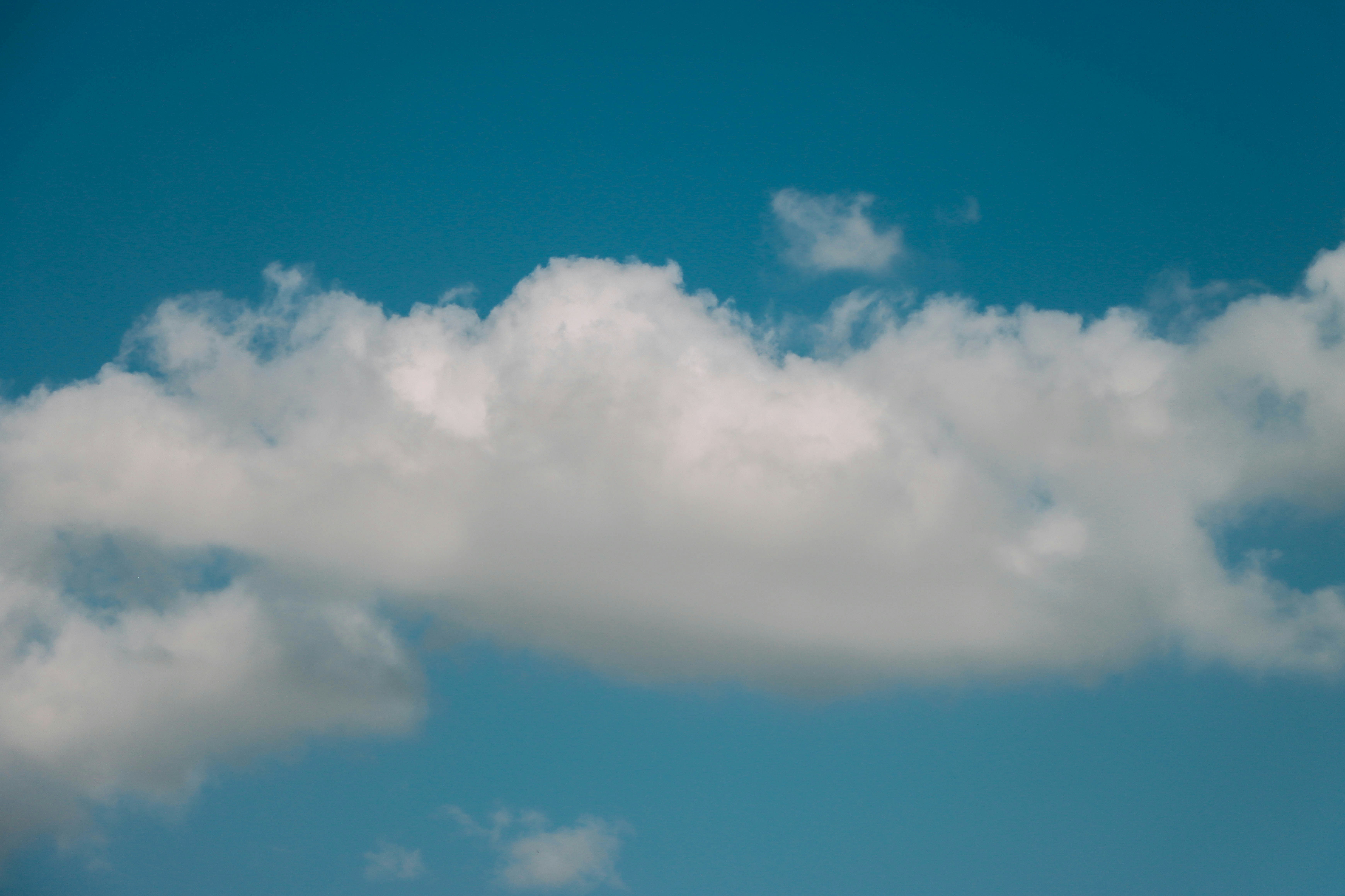 Vast blue sky with a soft, fluffy cloud sweeping across the frame, emphasizing open space and tranquility; suitable for a background or stock shot.