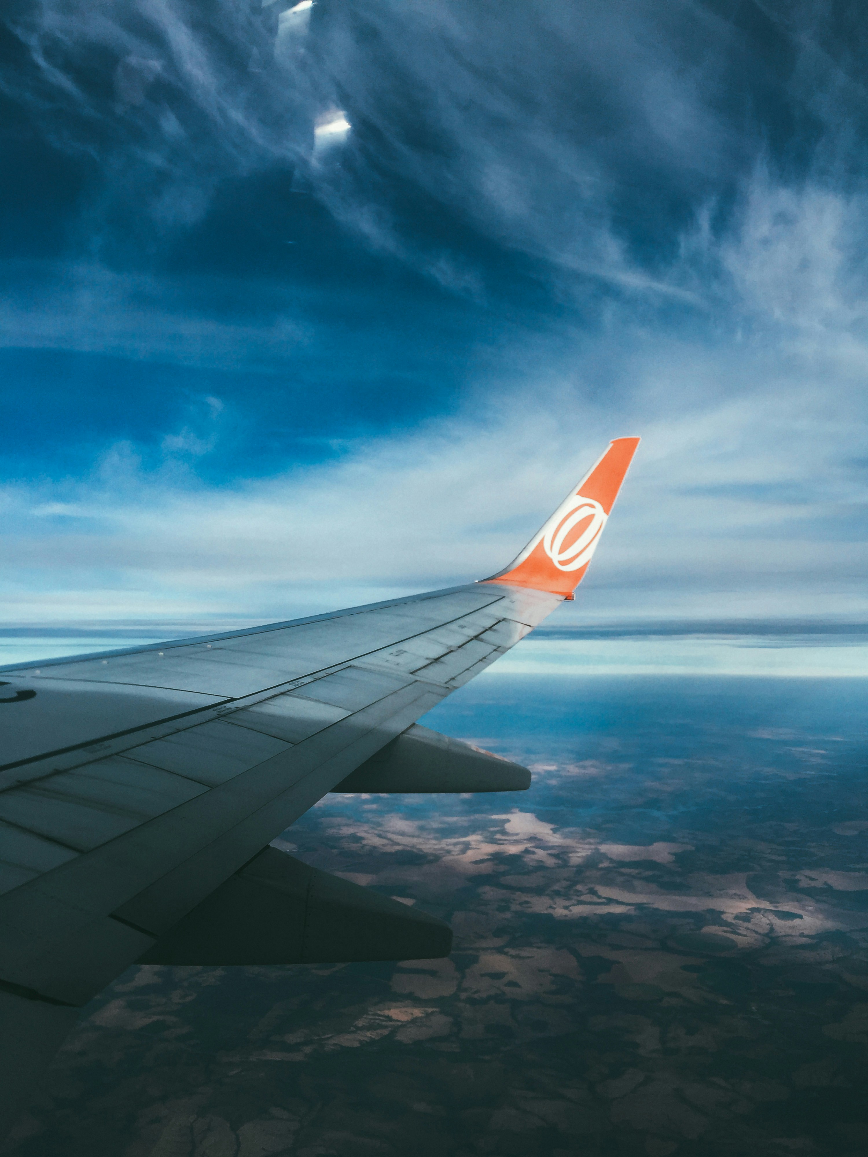 Wing over the World: An Orange Tail in a Sky-Blue Horizon