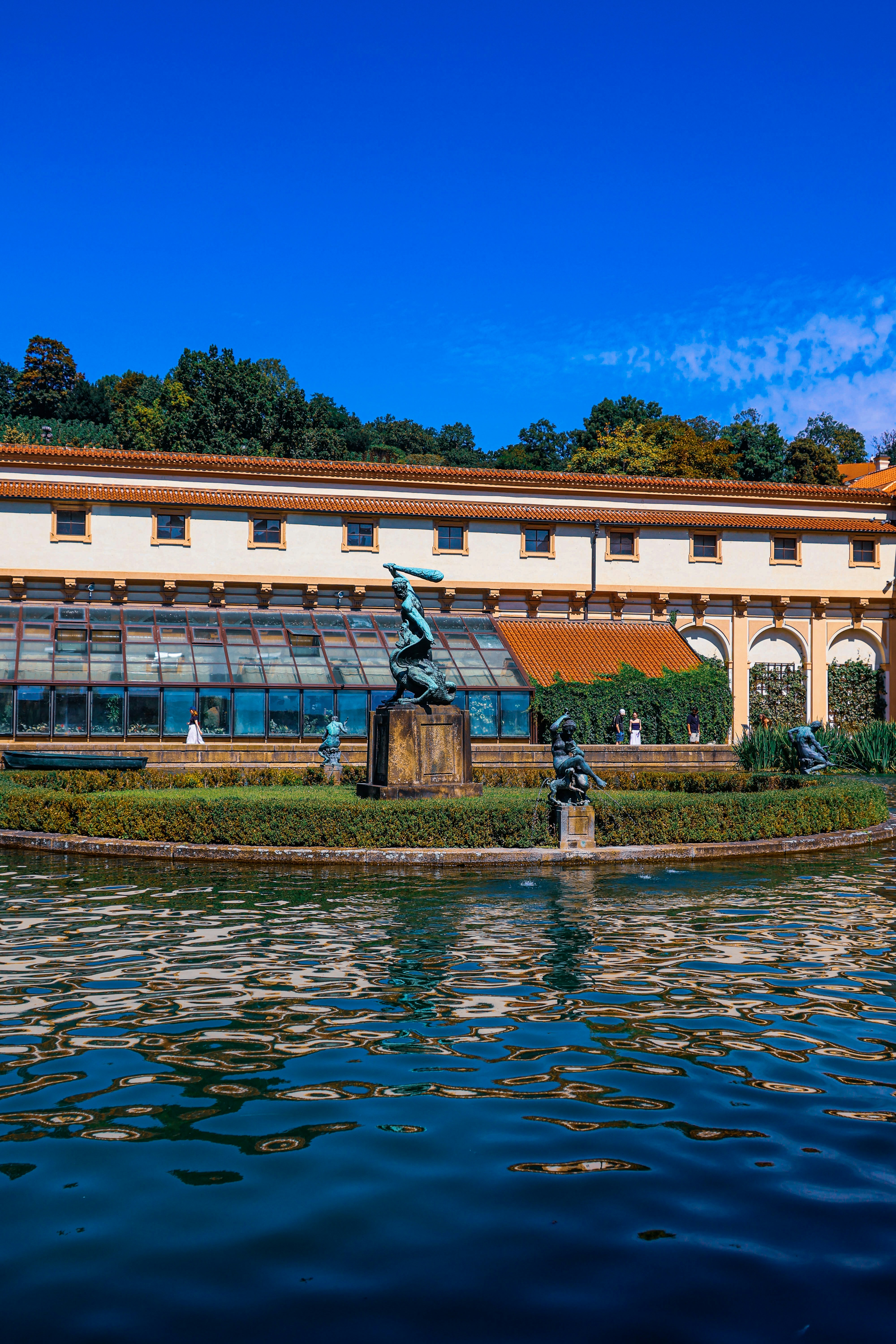 Statues and Glasshouse Reflections: A Serene Fountain Scene