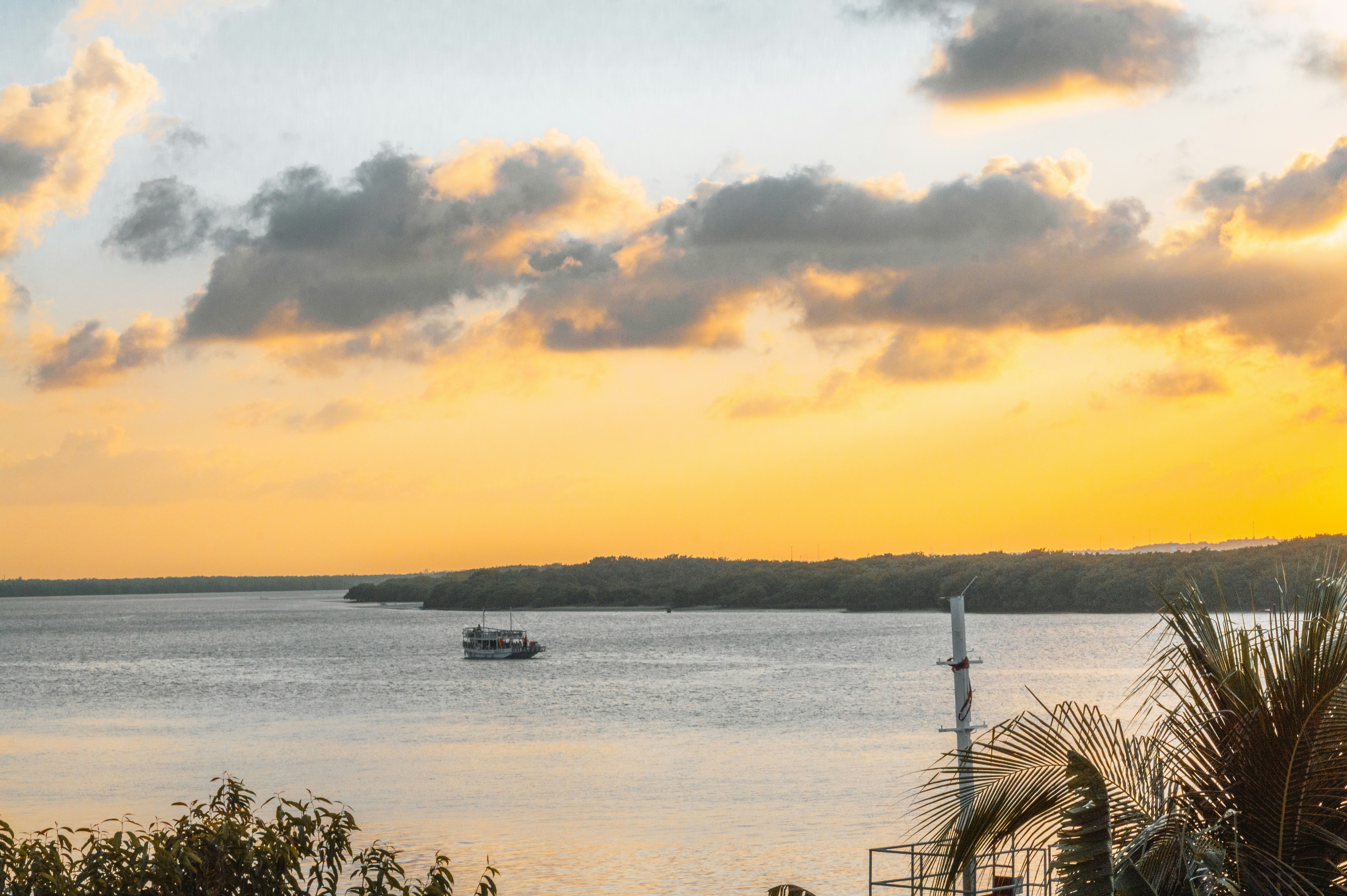 Sunset Passage: Boat on Calm Waters Beneath a Gold-Crested Sky