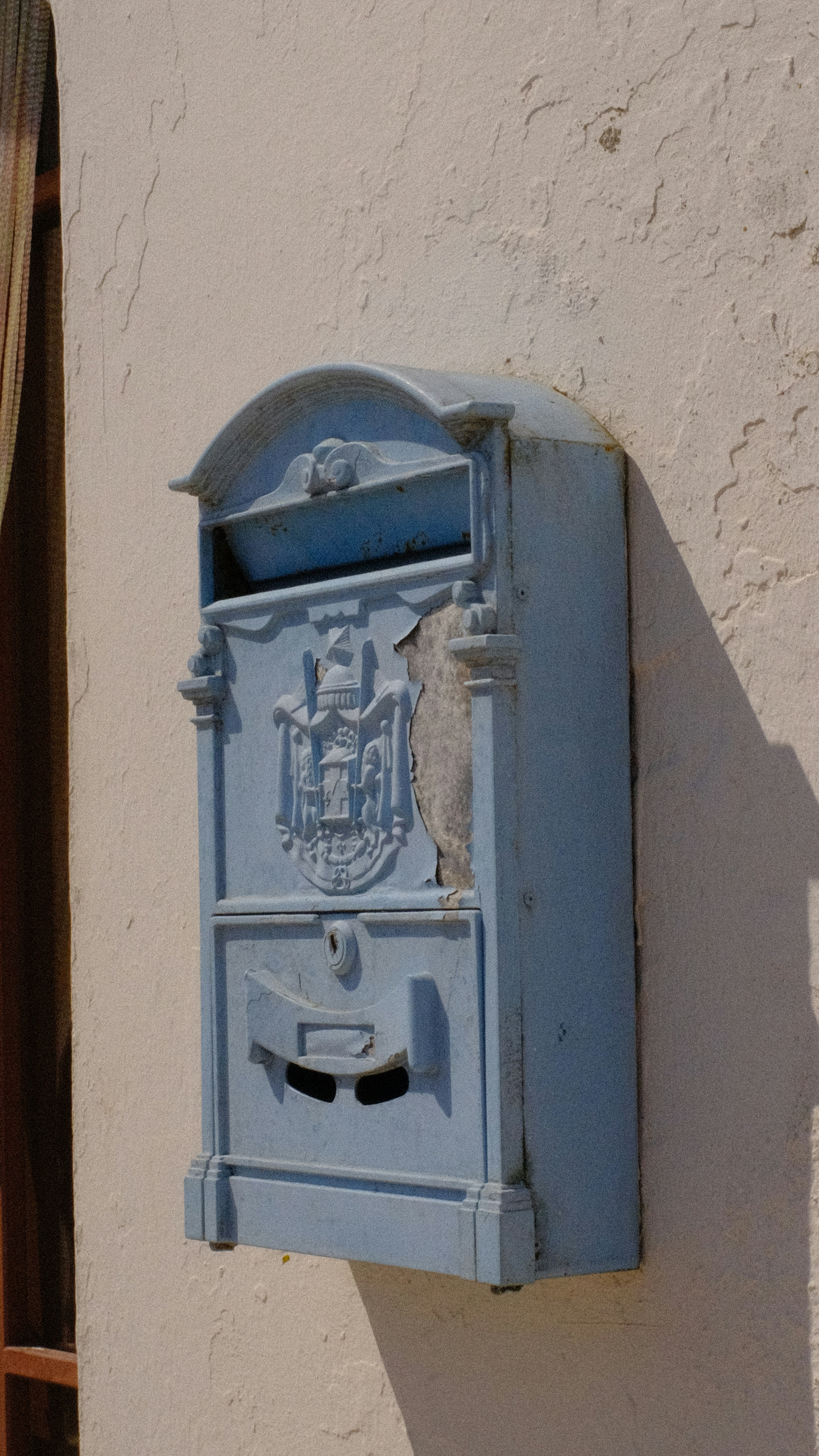 Blue Postal Relic on Sunlit Stucco Wall