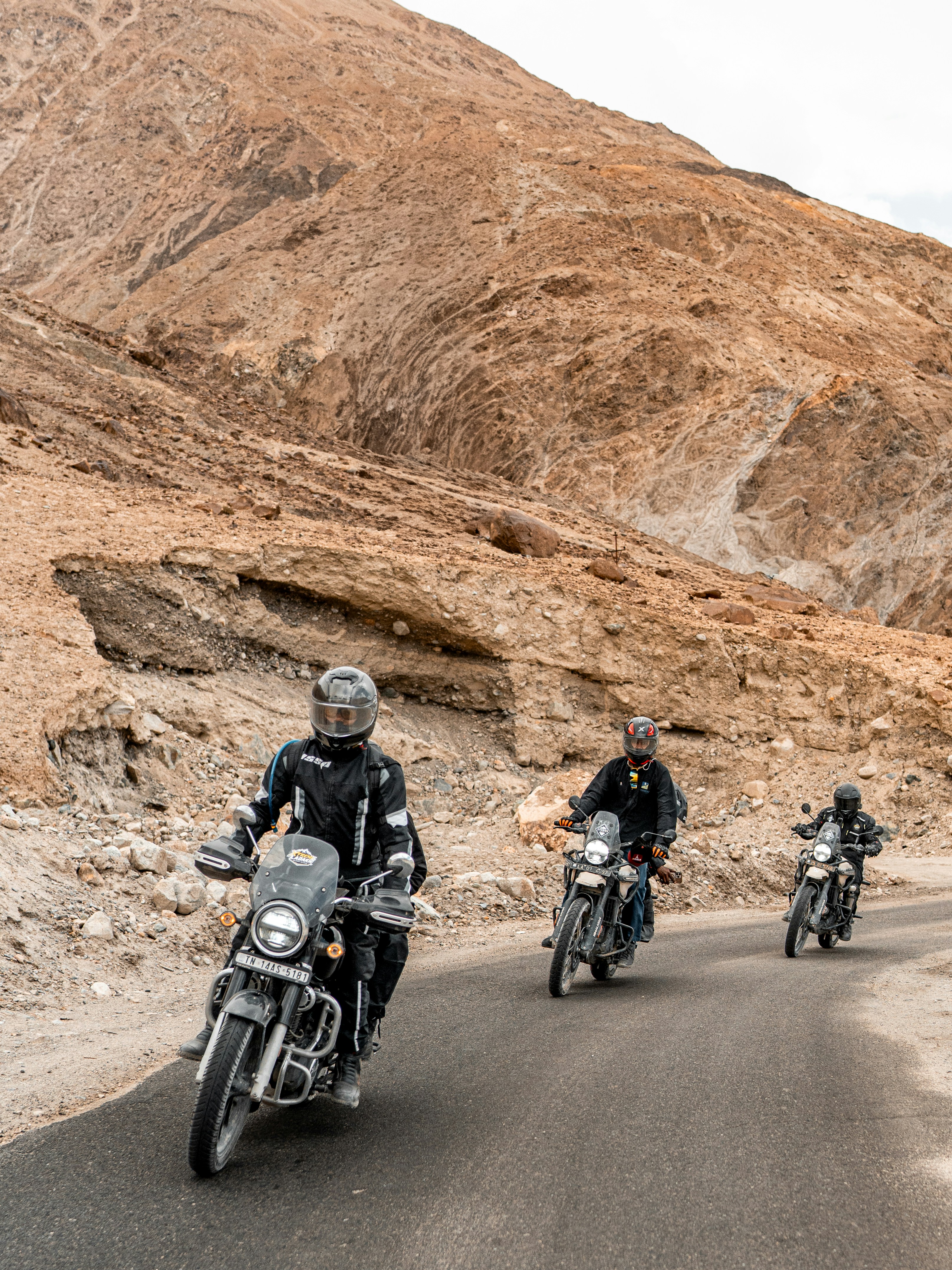 Three Riders carve through a rocky hillside on a winding mountain road