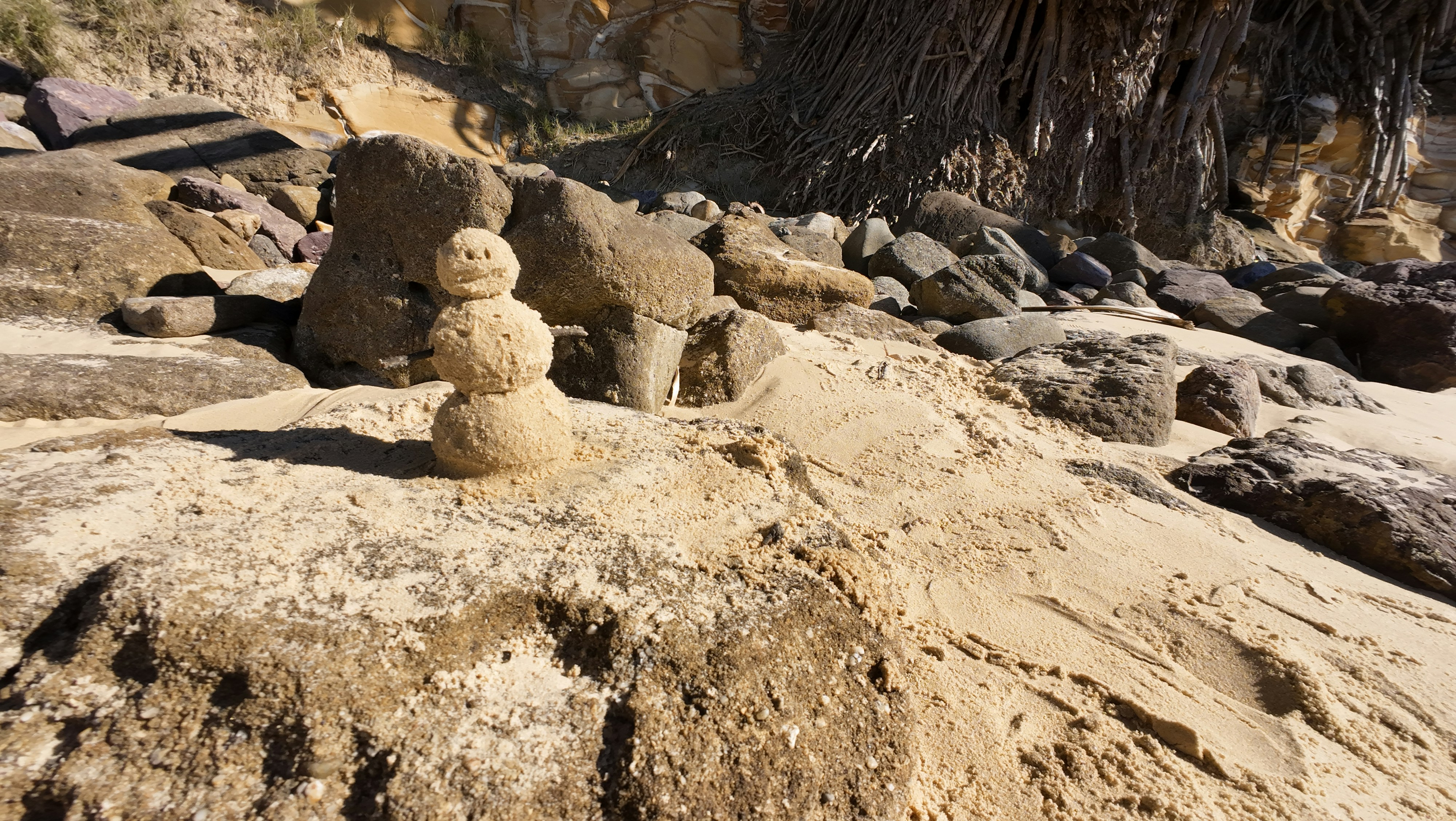 Tiny Sand Figure Stands Guard on a Rocky Shore