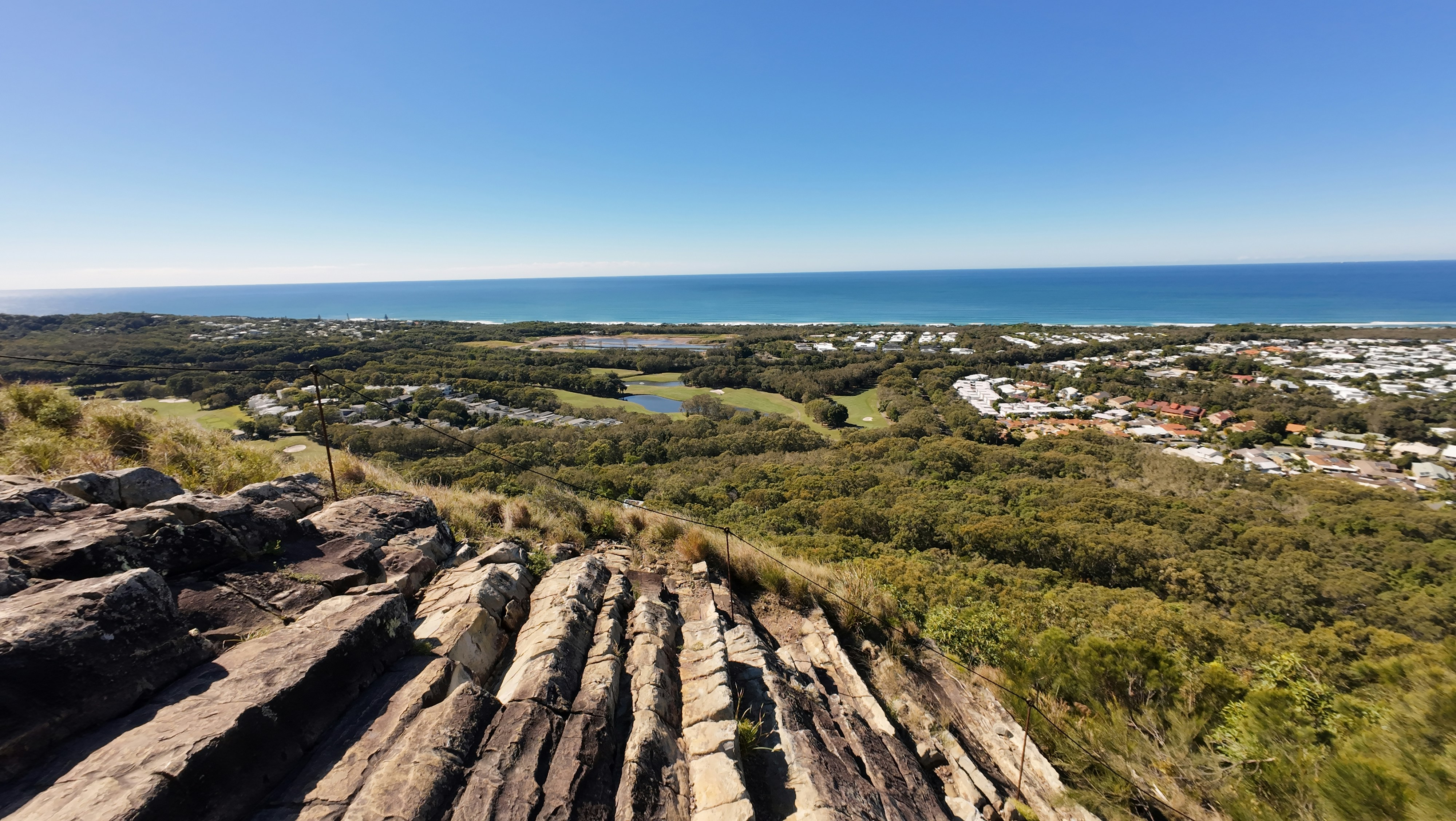 Clifftop Vista: Tidal Plain Stretch Beneath a Clear Coastal Sky
