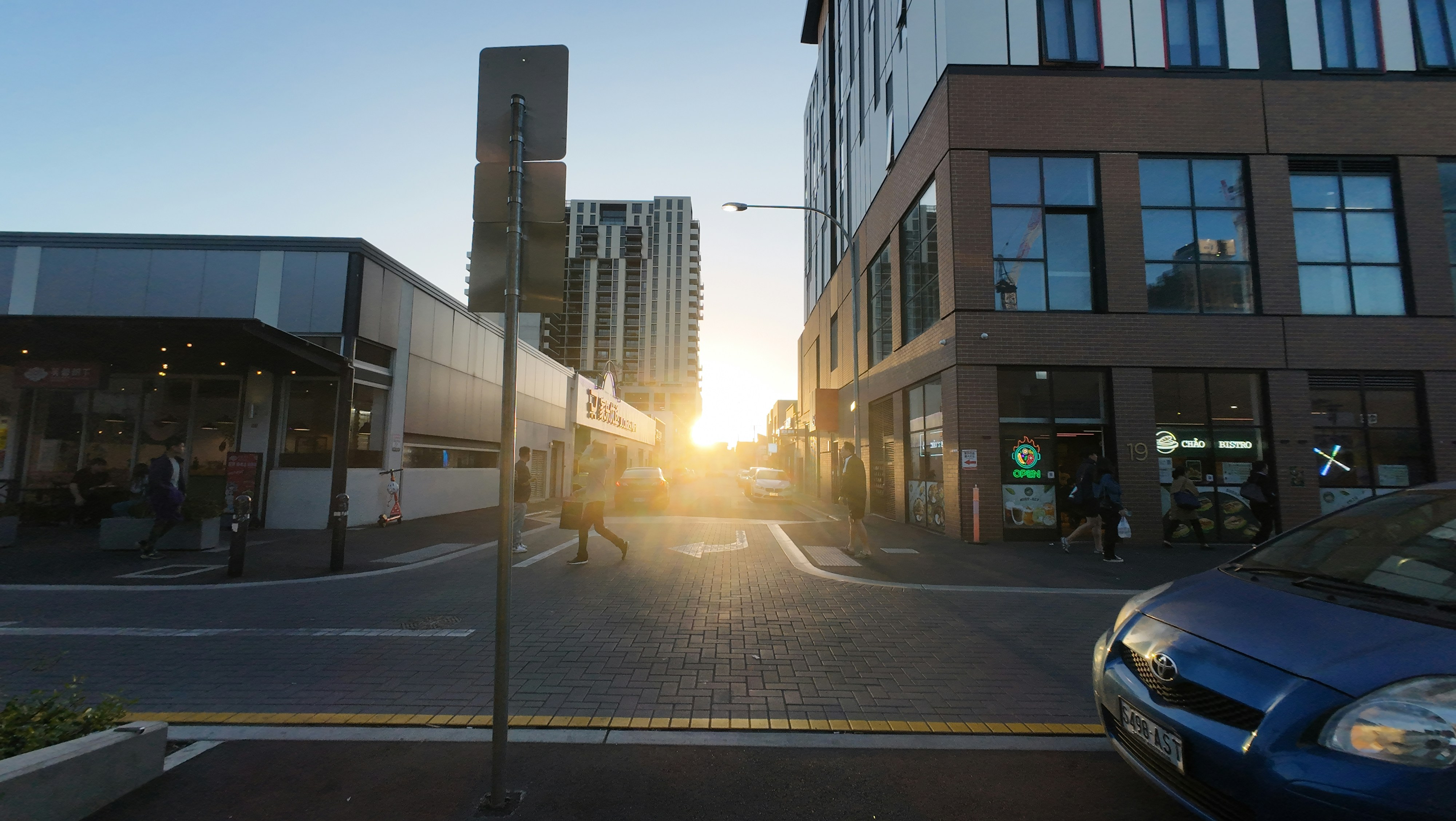 Sunlit Street Confluence: Crossing Into a Busy Modern Corridor