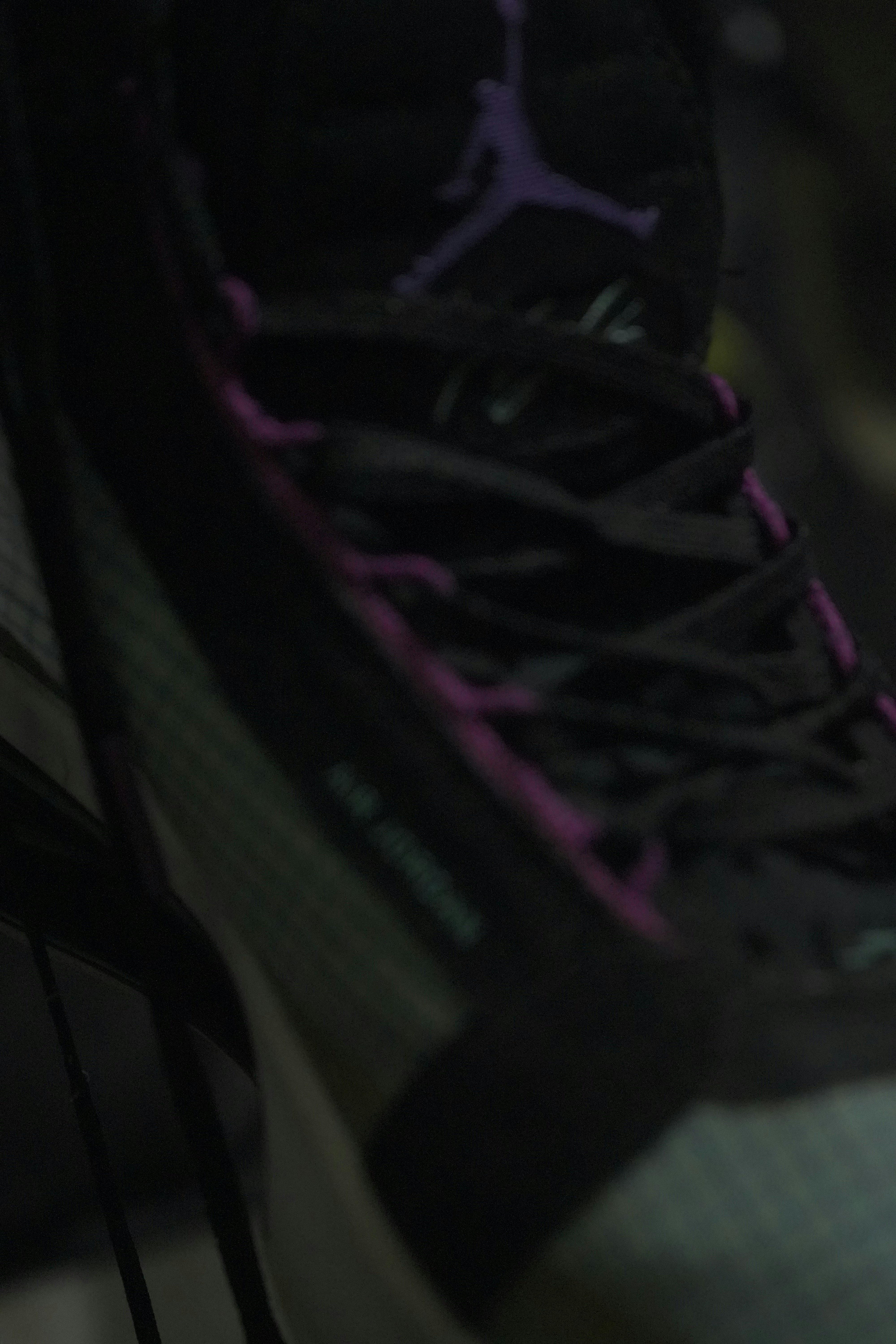 A black high-top sneaker with purple laces and a purple logo.