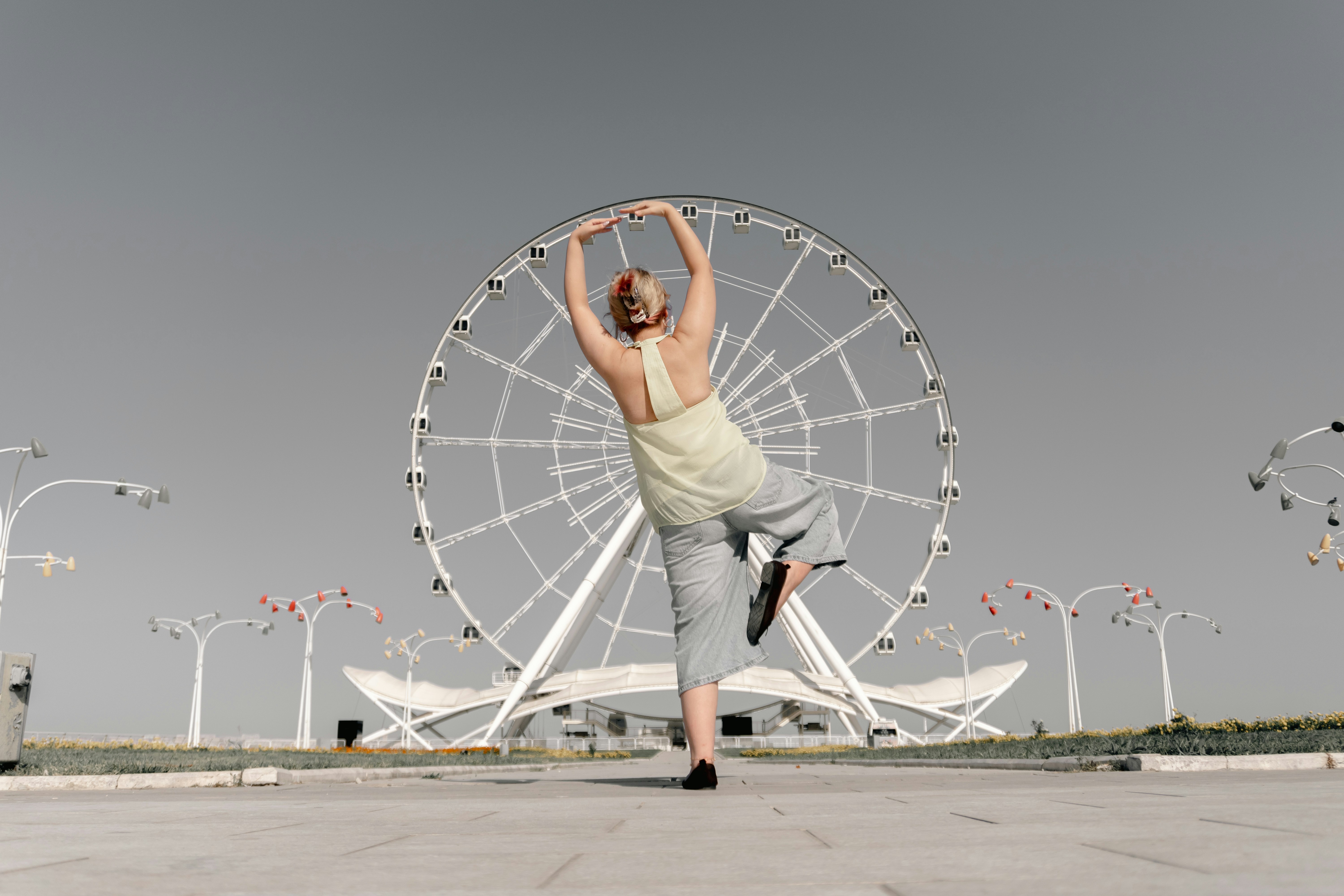 Center Stage: A Dancer Reaches Up Against a Giant Ferris Wheel