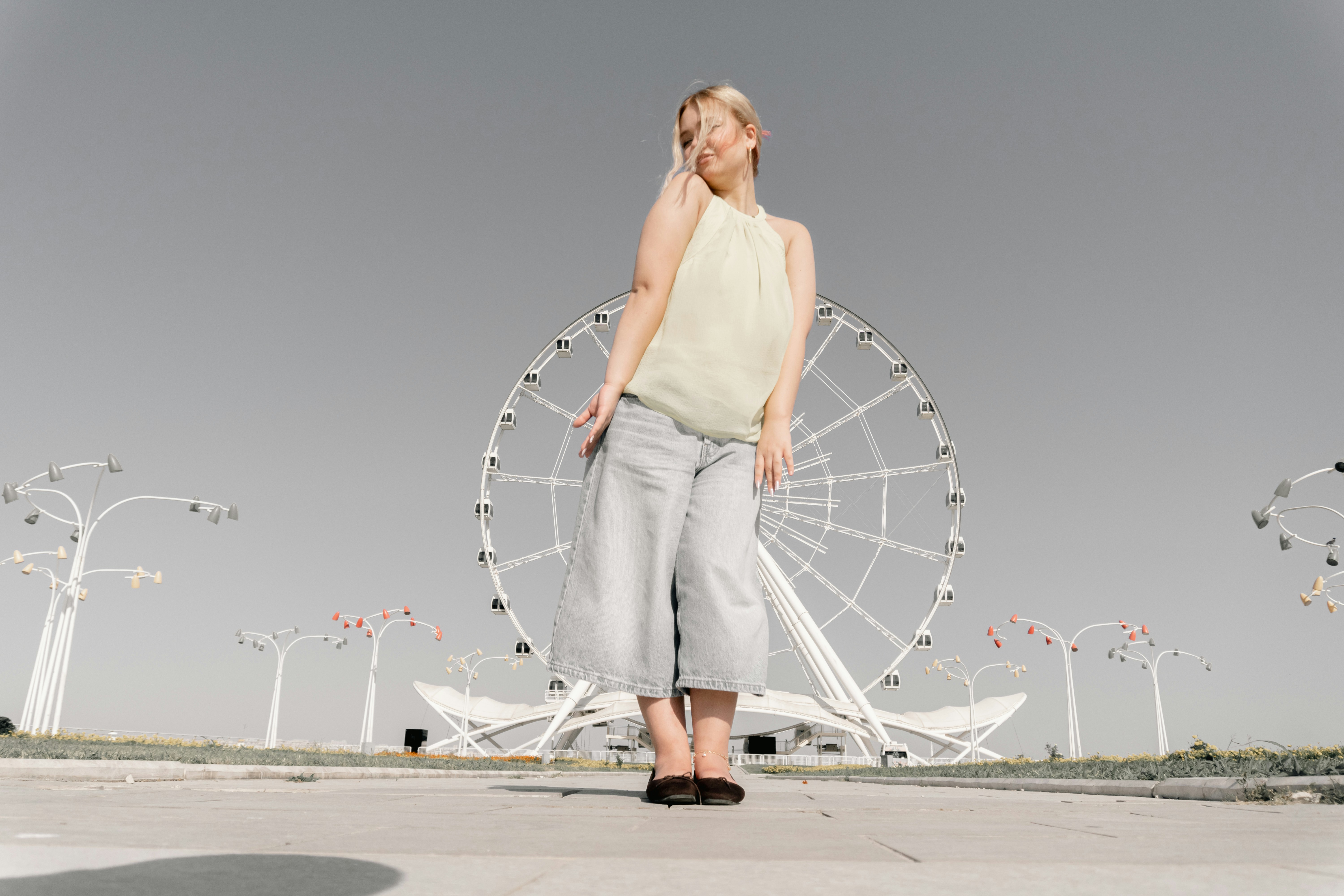 Towards the Sky: A Woman in a Light Top Stands Before a Giant Ferris Wheel