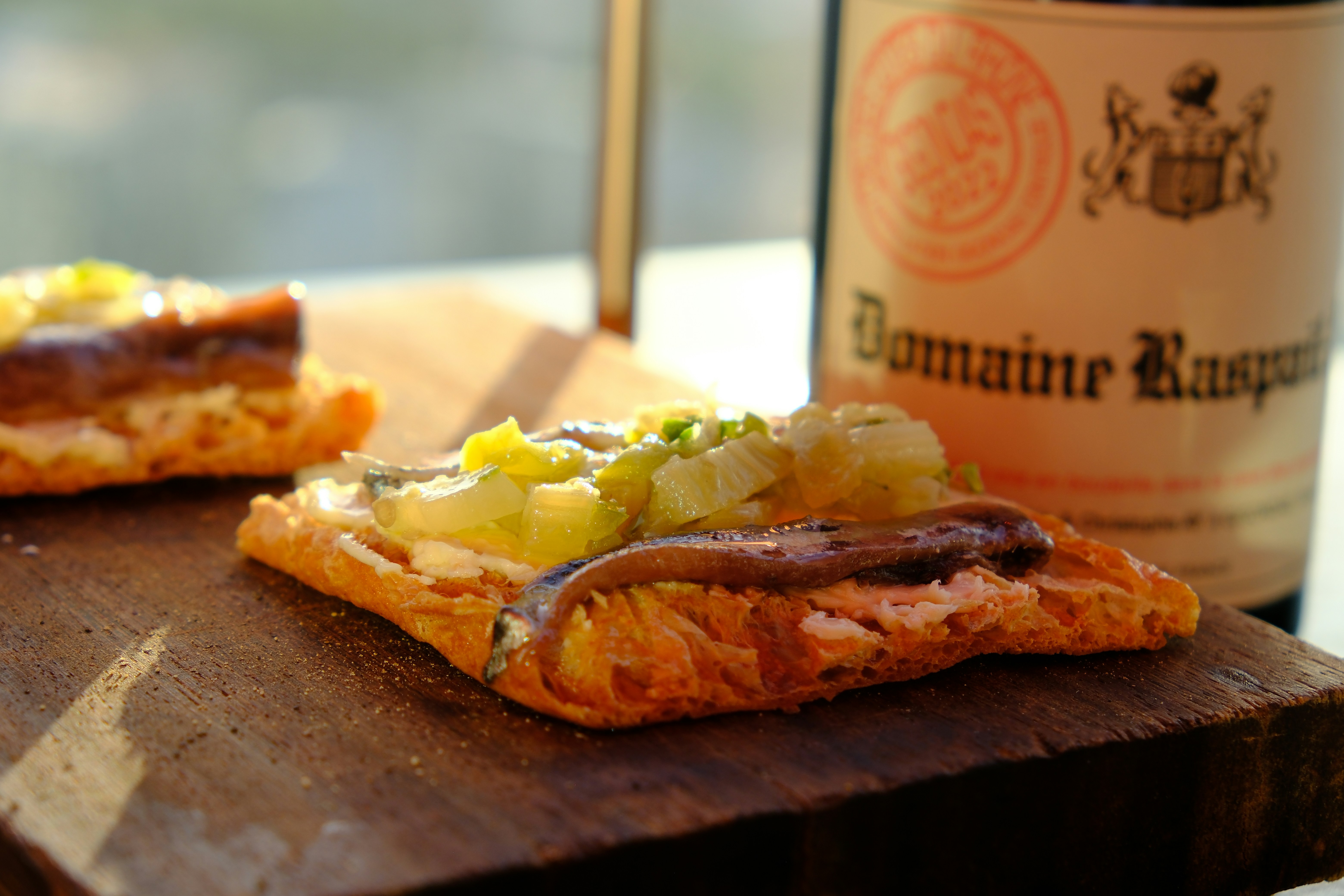 Snack on a Sideboard: A Crispy Topped Bite with a Bottle in the Background