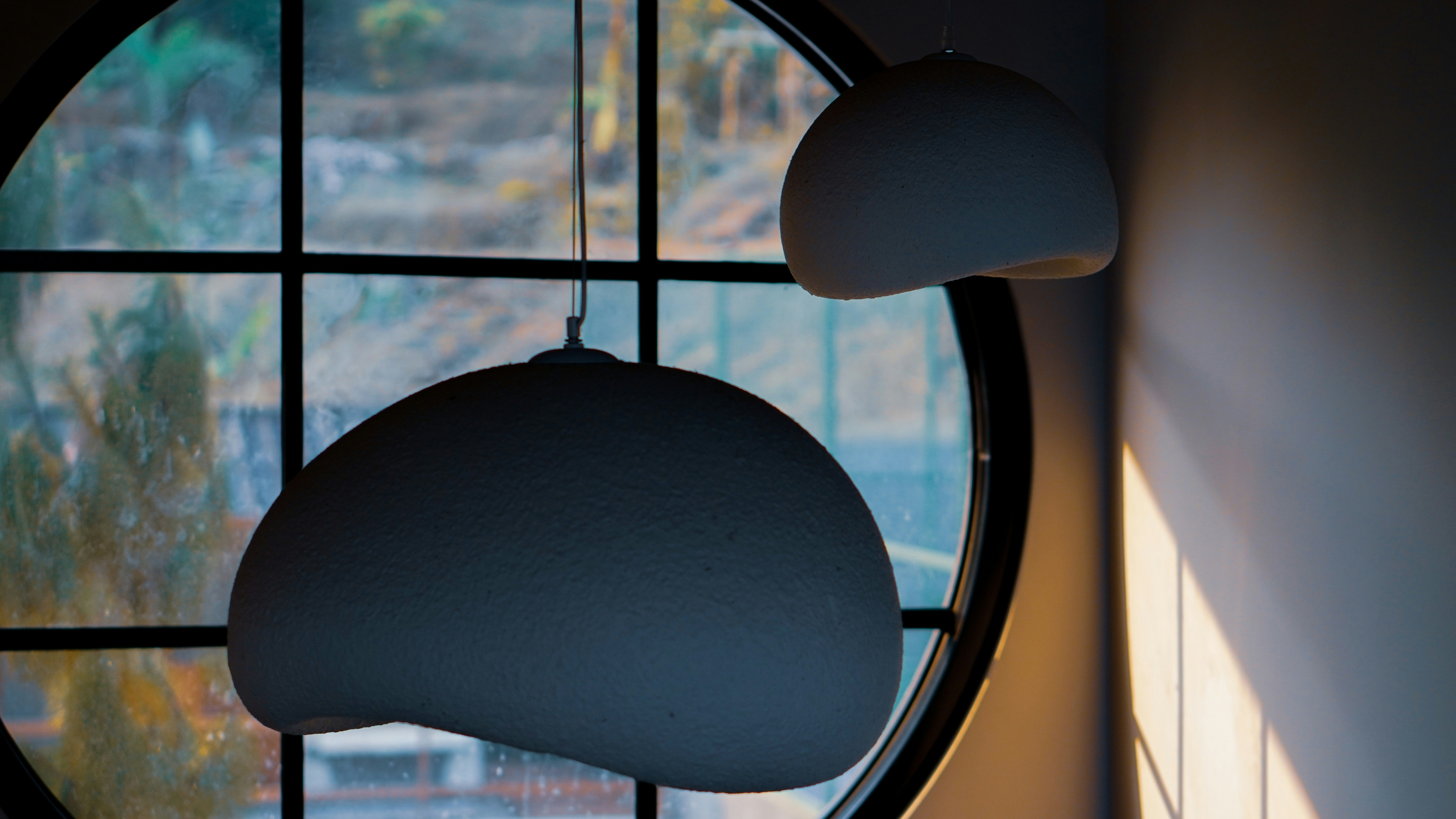 Circular window, warm glow: a studio-lit interior with layered pendant lamps