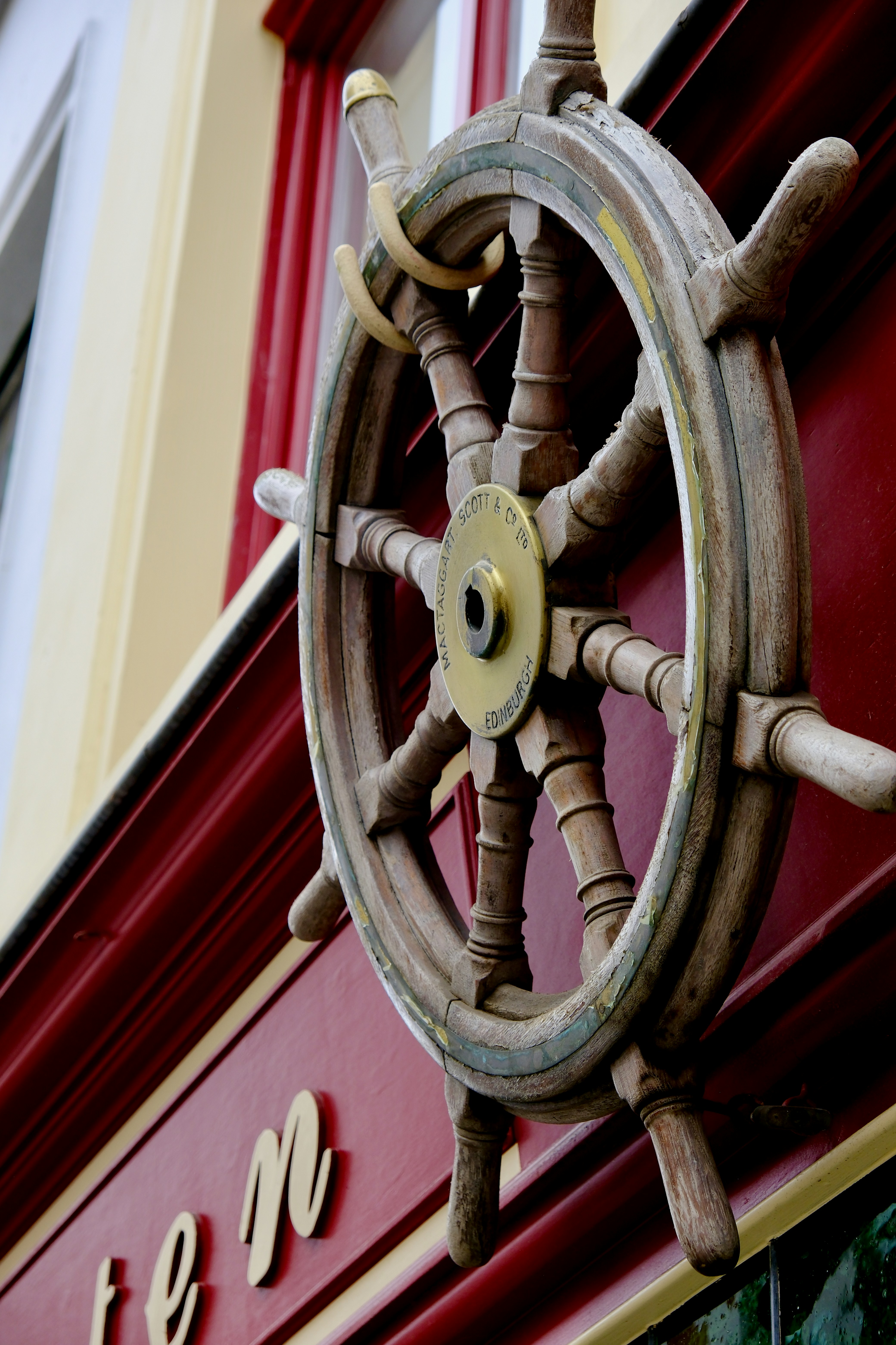 Steering Wheel of Time: A Weathered Ship’s Wheel Graces a Red-Faced Façade